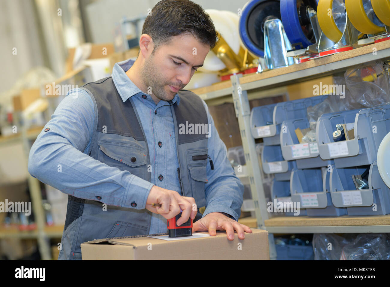 manager taping up a cardboard box in a warehouse Stock Photo - Alamy