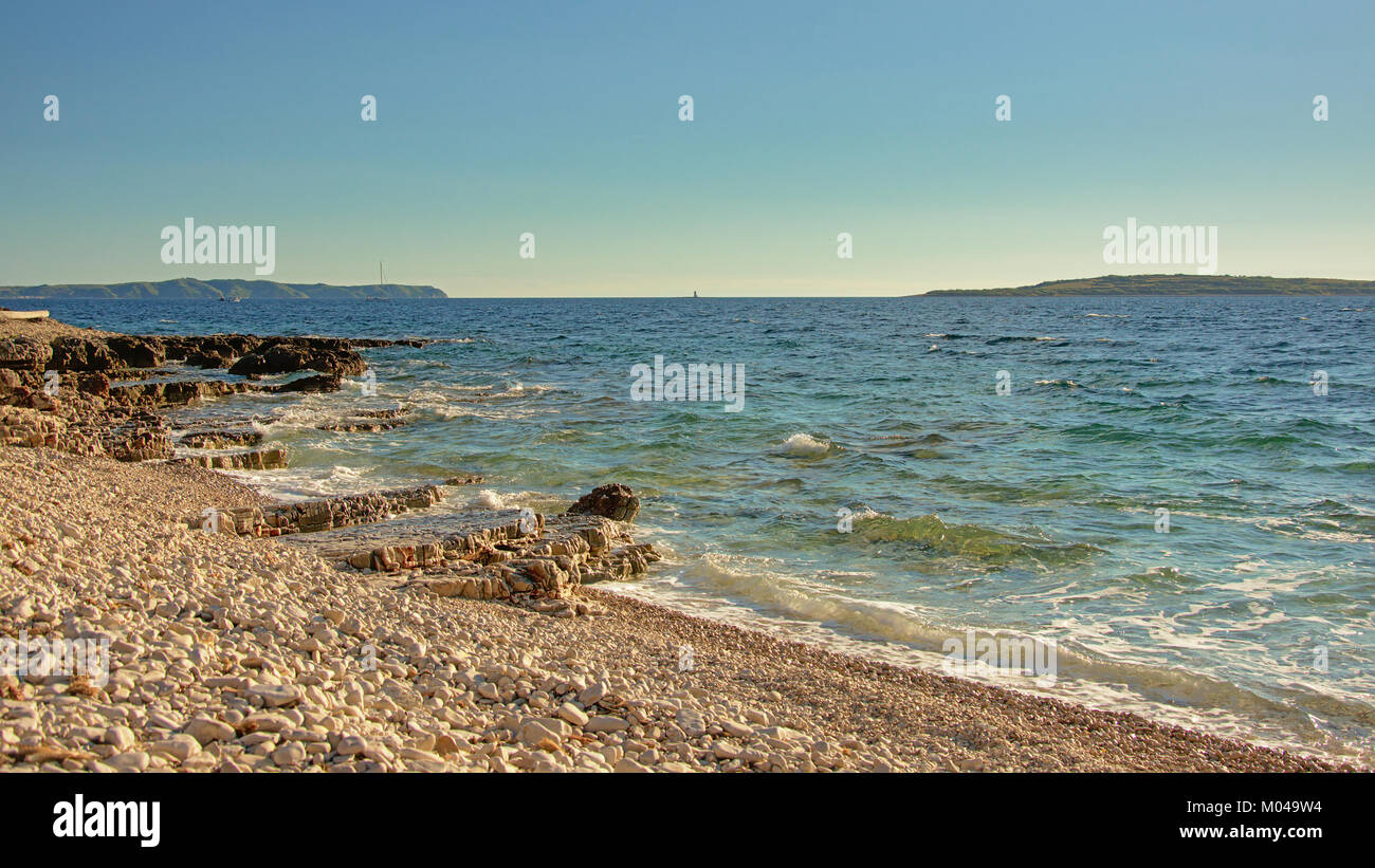 Beach with volcanic rocks and pebbles along the Adriatic sea with ...