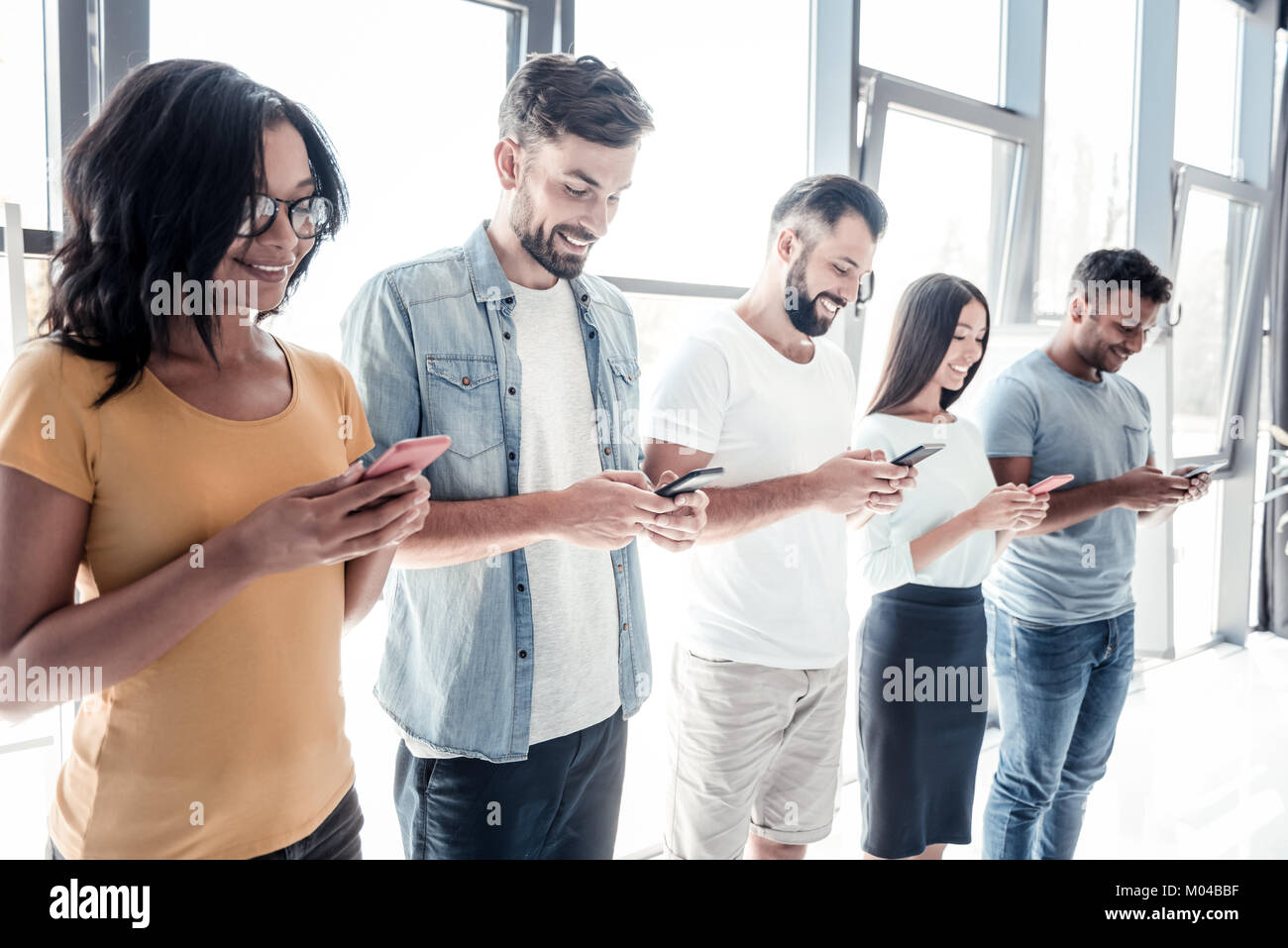 Smiling people using smartphones together Stock Photo - Alamy