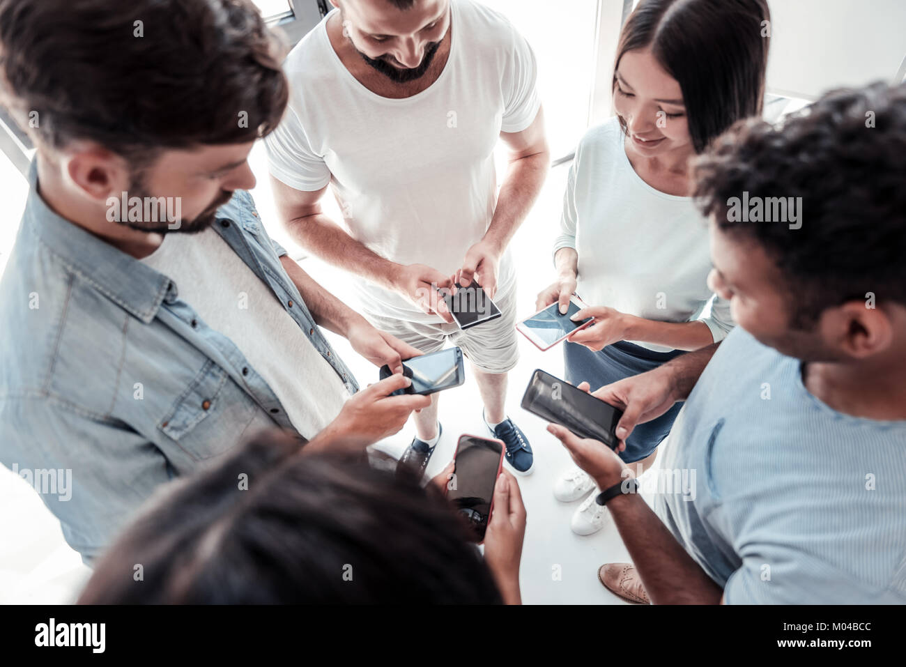 Group of young people using smartphones together Stock Photo - Alamy