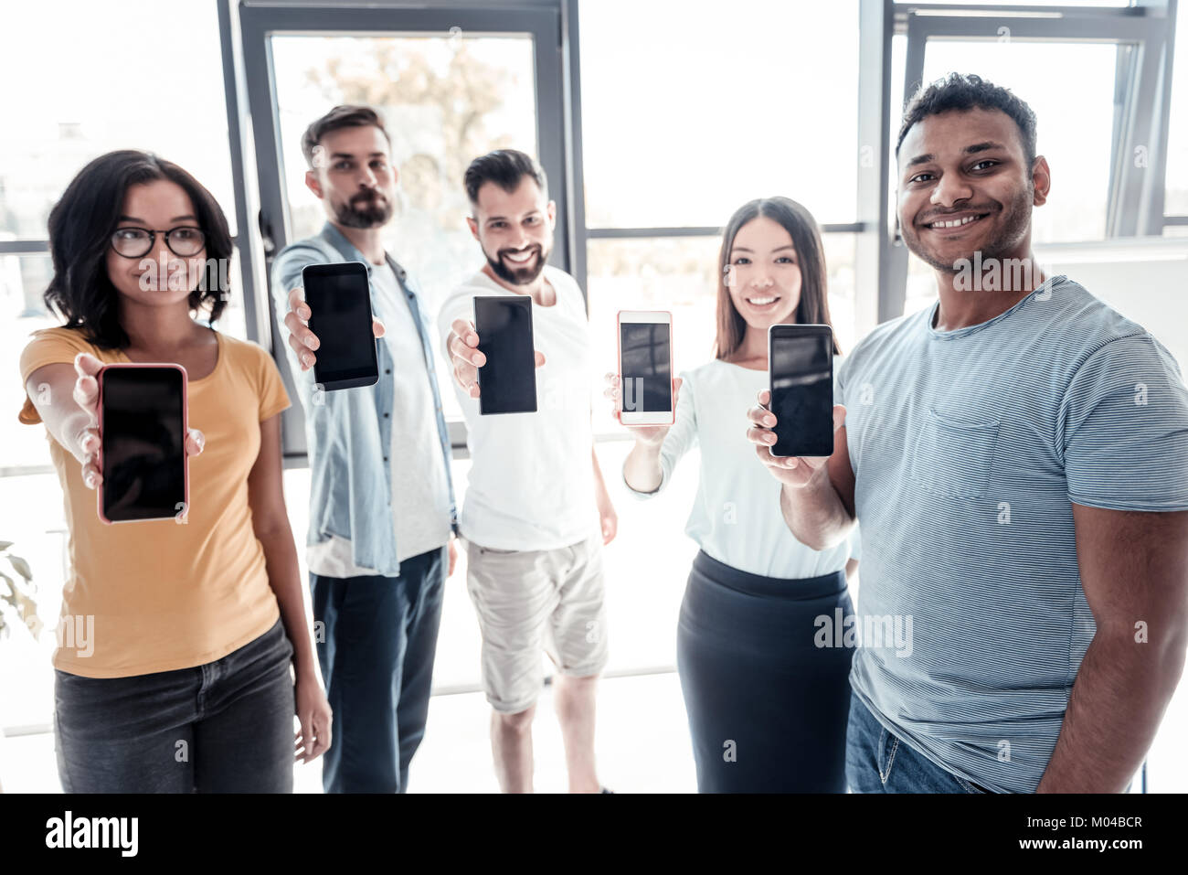 Happy millennial people demonstrating their smartphones Stock Photo - Alamy
