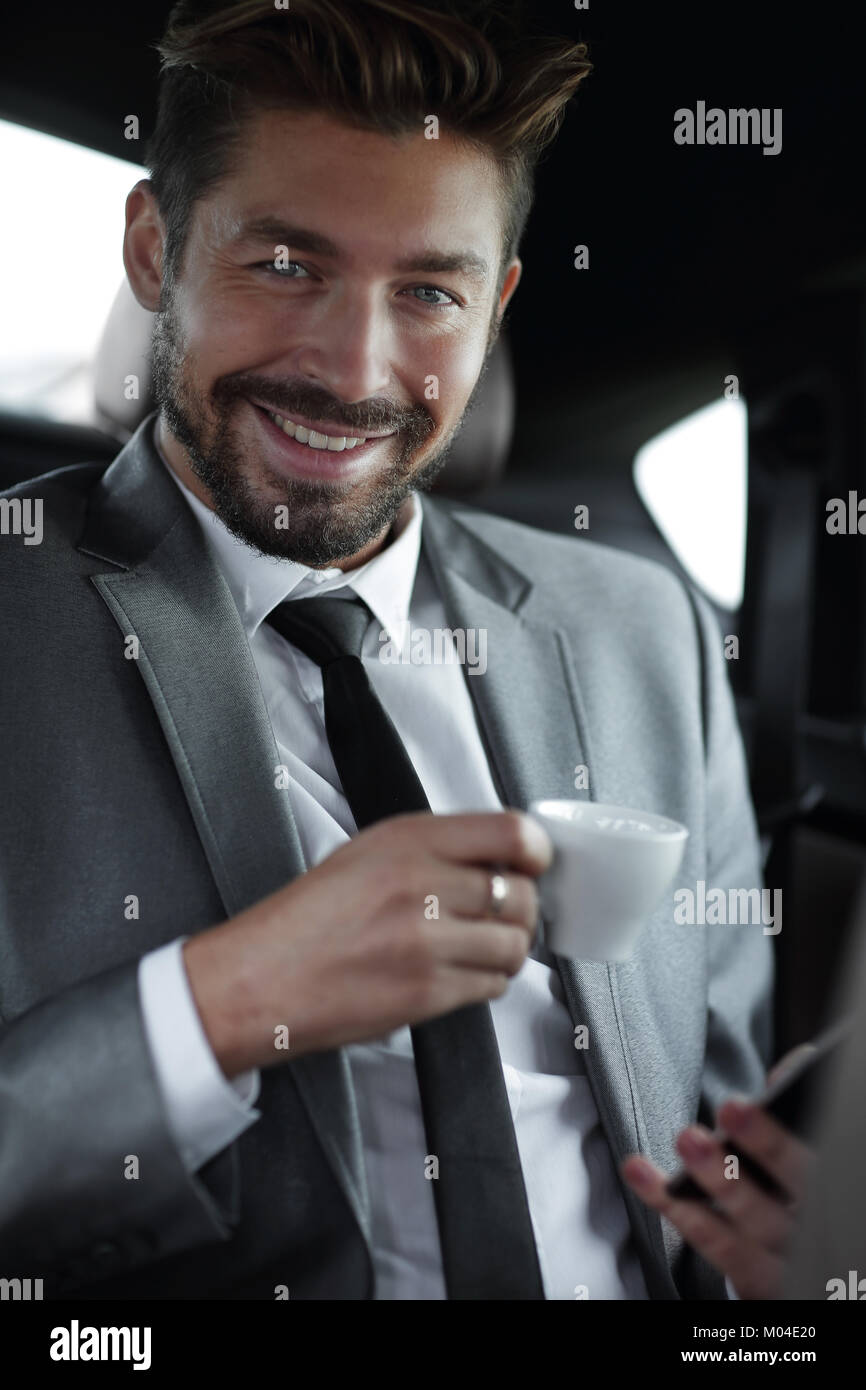 Businessman drinking coffee in the back seat of a car Stock Photo - Alamy