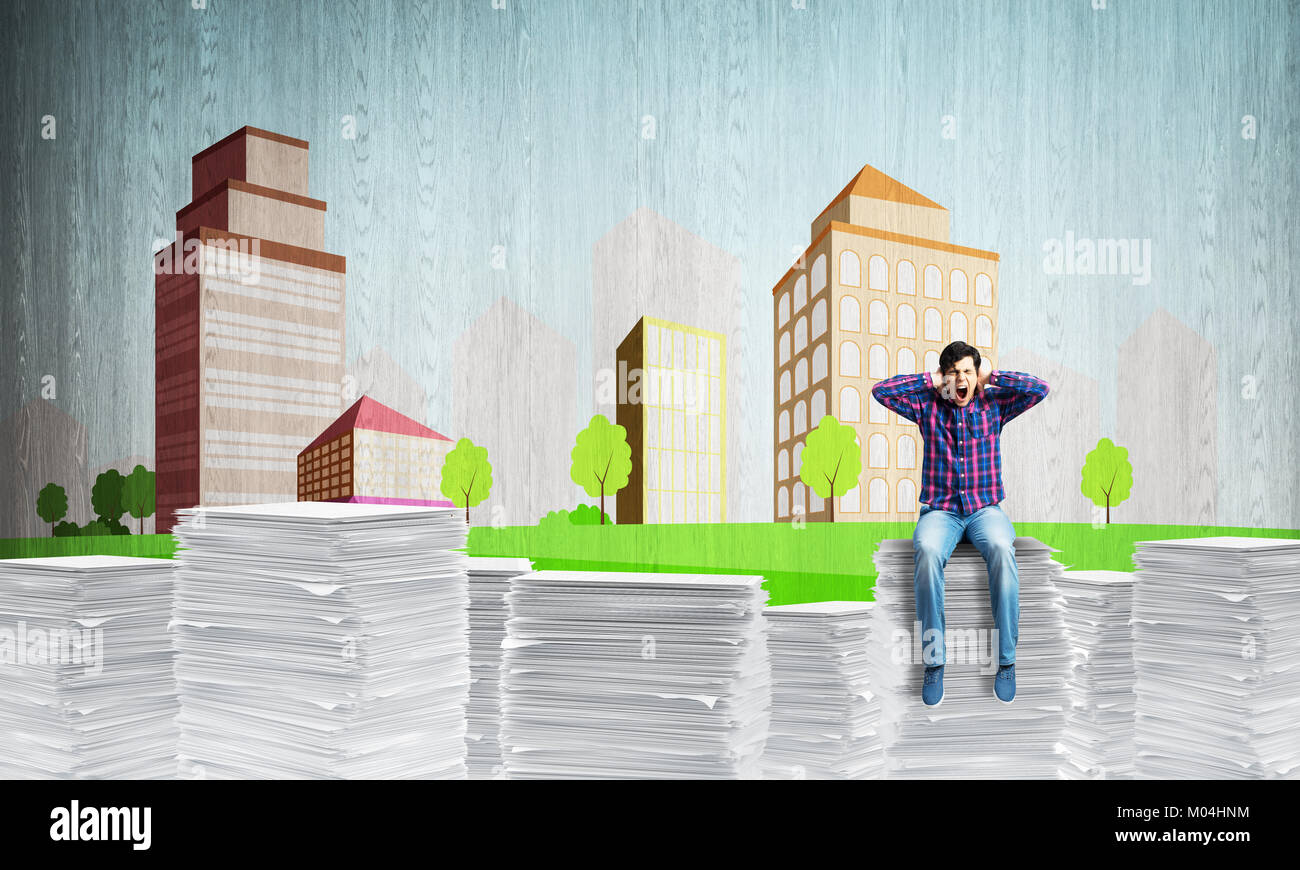 Young man sitting on pile of paper documents Stock Photo - Alamy