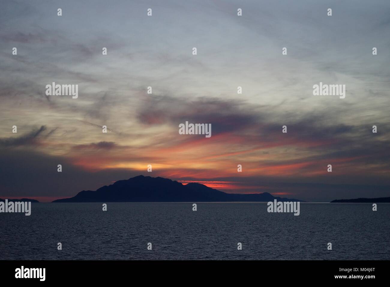Pastel colored sunset sky over the distant rocks in the sea - view from ...