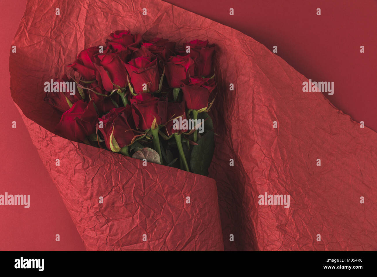 top view of bouquet of roses in wrapping paper isolated on red Stock ...