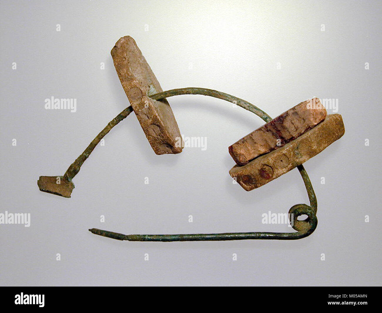 This bronze fibula, a safety pin adorned with amber segments, is an ...
