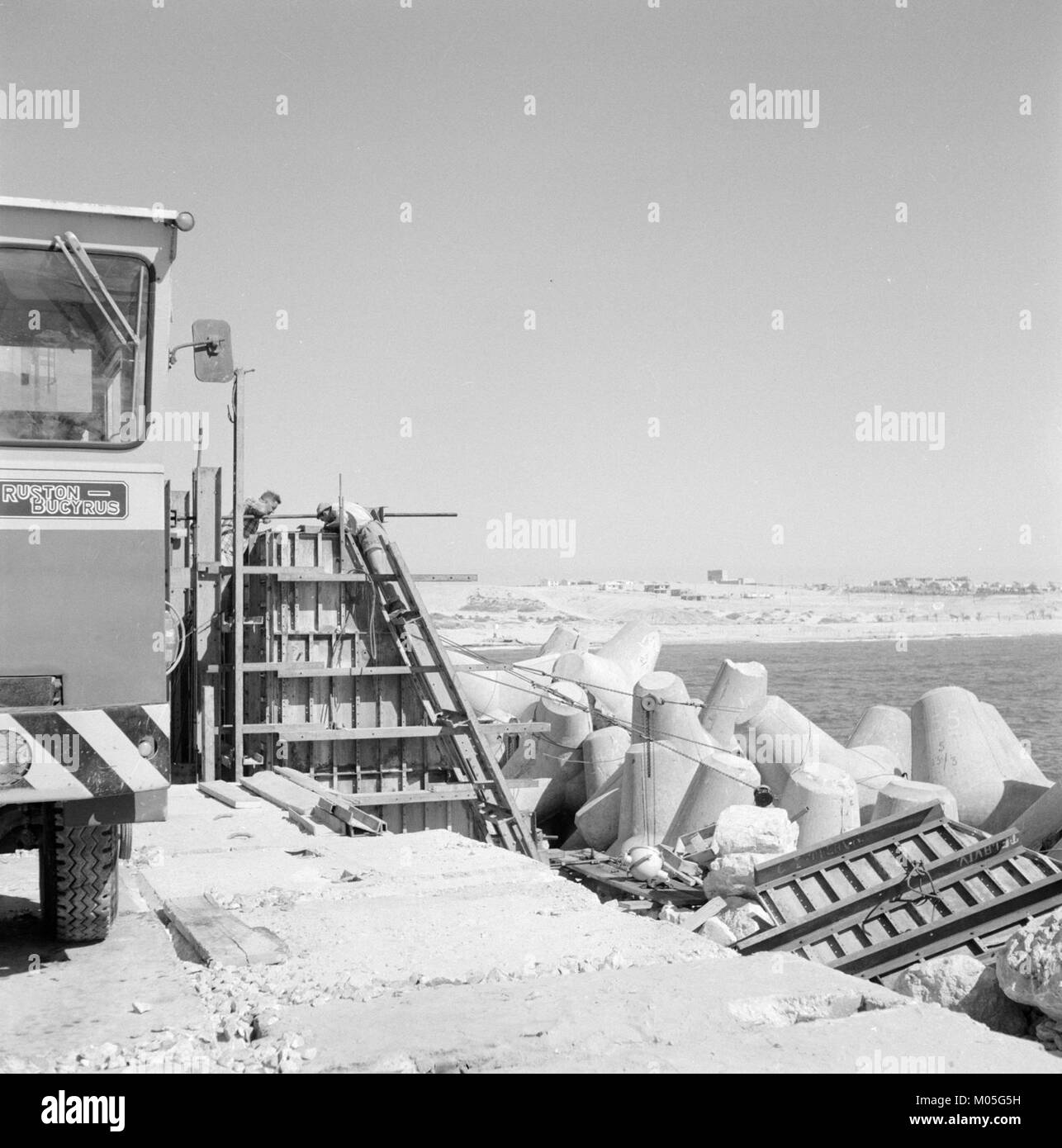 This historical image shows construction workers laboring at a harbor ...
