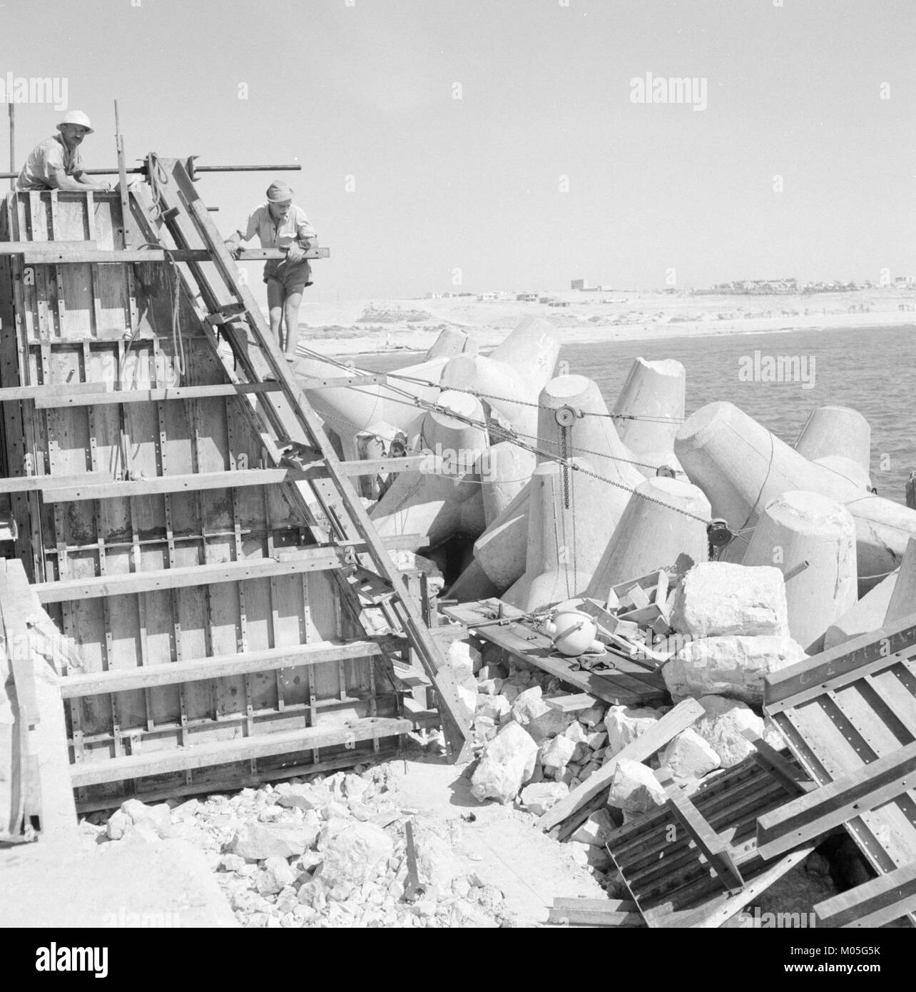 This photograph depicts construction workers working at a harbor ...