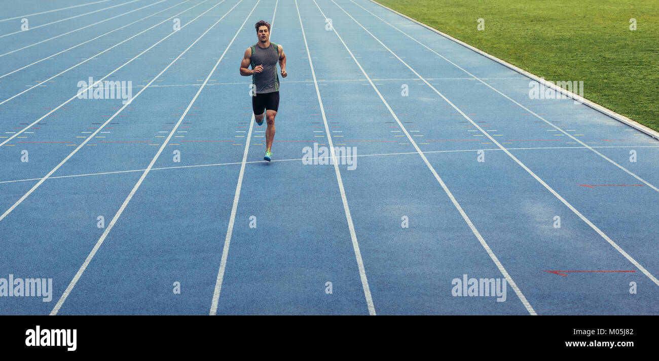 Athlete running on an all-weather running track alone. Runner sprinting ...