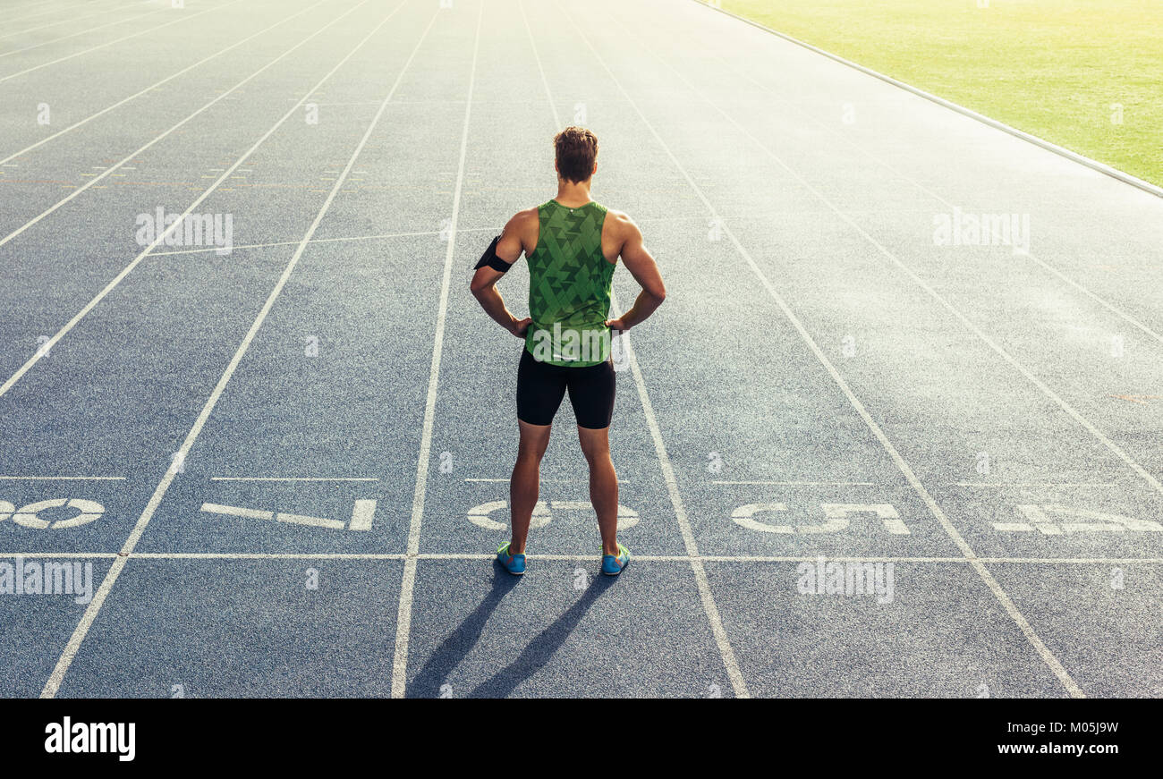 Rear view of an athlete standing on an all-weather running track ...