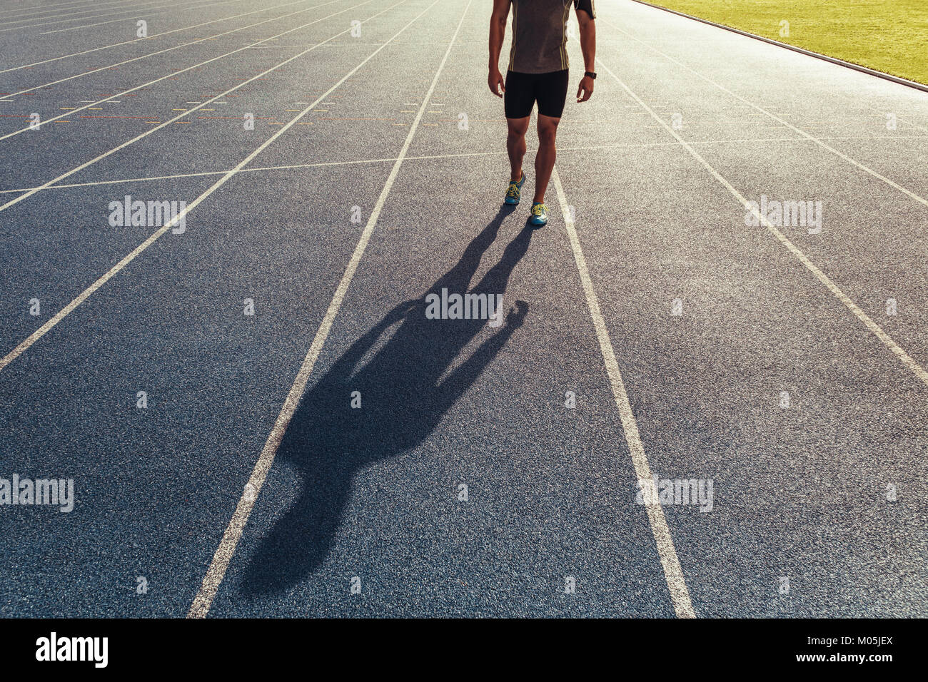 Athlete walking on an all-weather running track listening to music ...