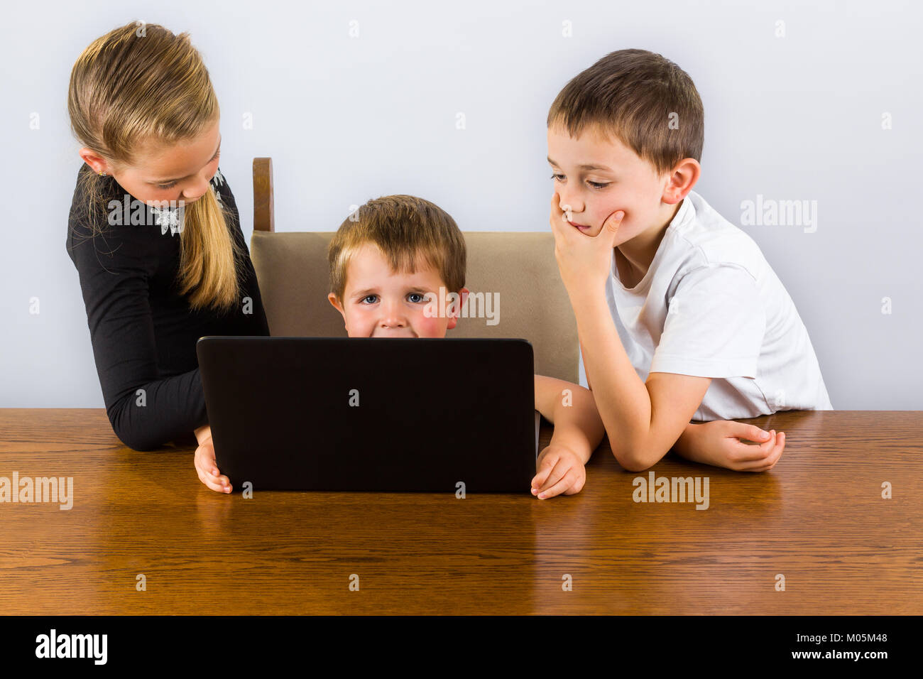 happy little boy with a laptop while getting help from his older sister ...