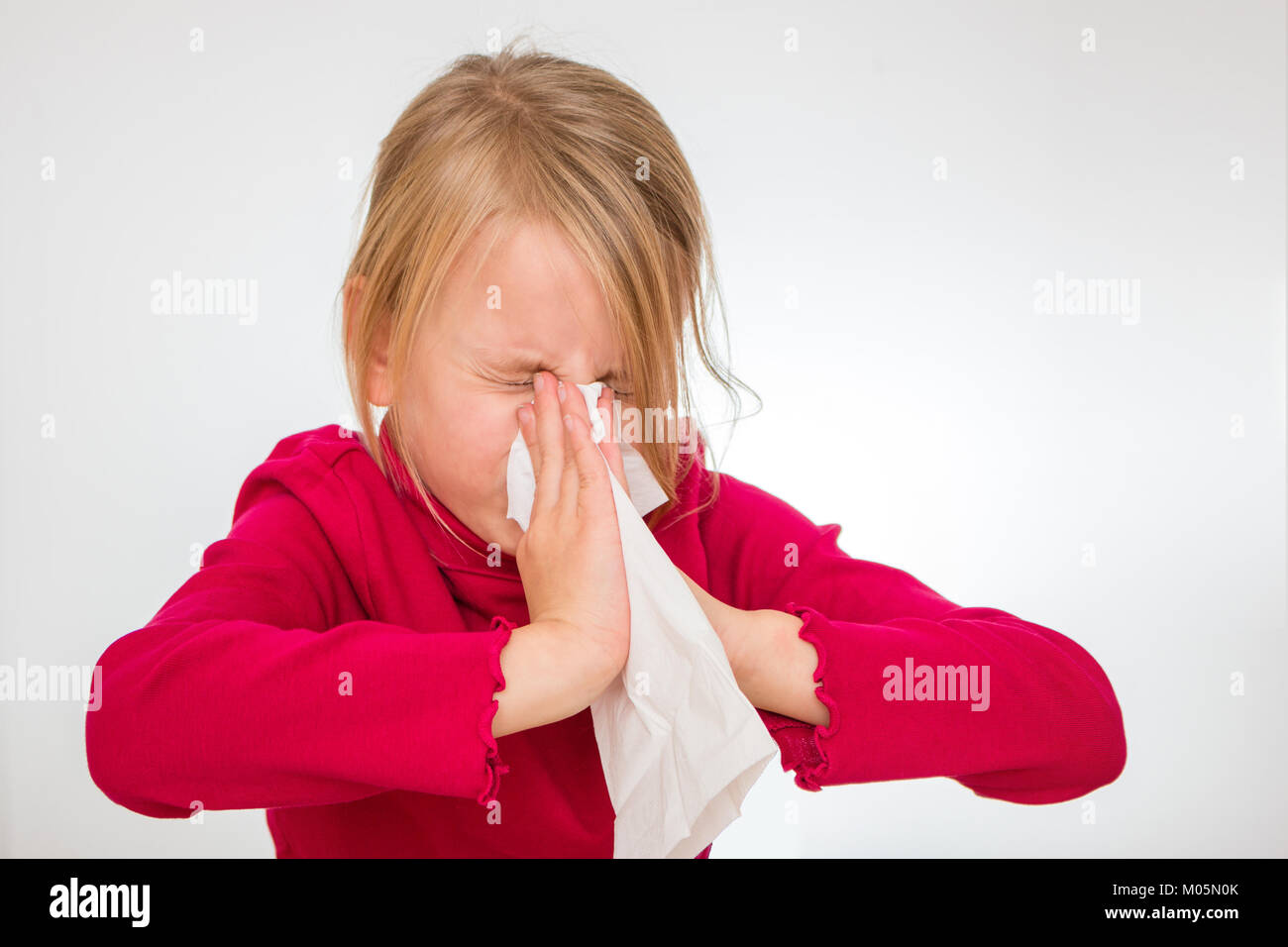 A girl is biting into a white handkerchief. She is 7 years old and ...