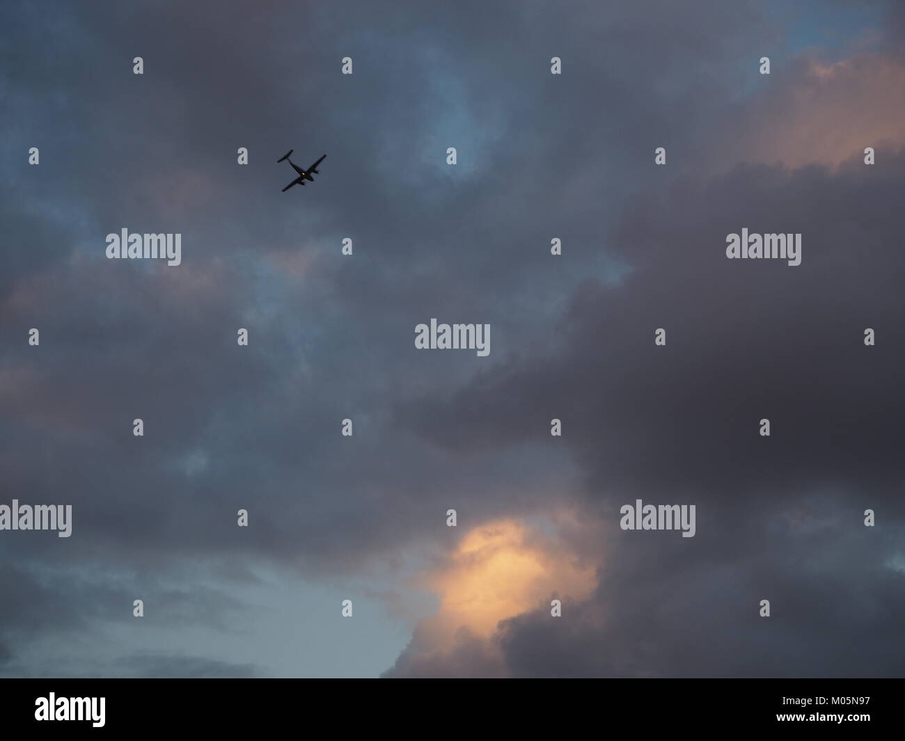 an airplane flying west at evening tine on a grey cloudy sky Stock ...