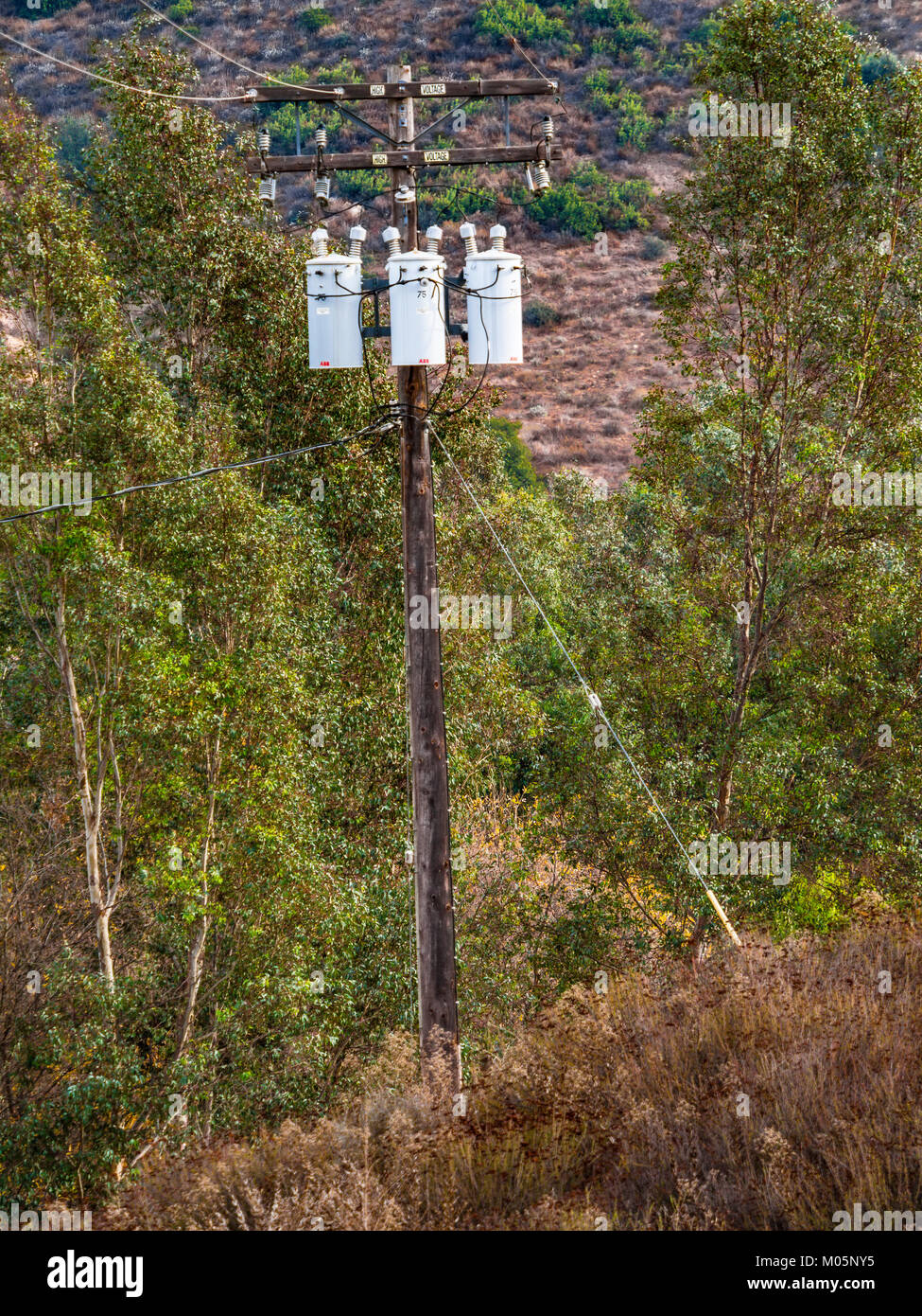 three high voltage electrical power transformers on pole in rural area ...
