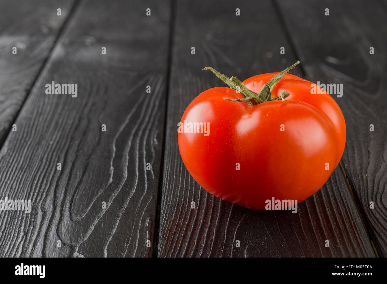 Ripe red tomato on a black background Stock Photo - Alamy