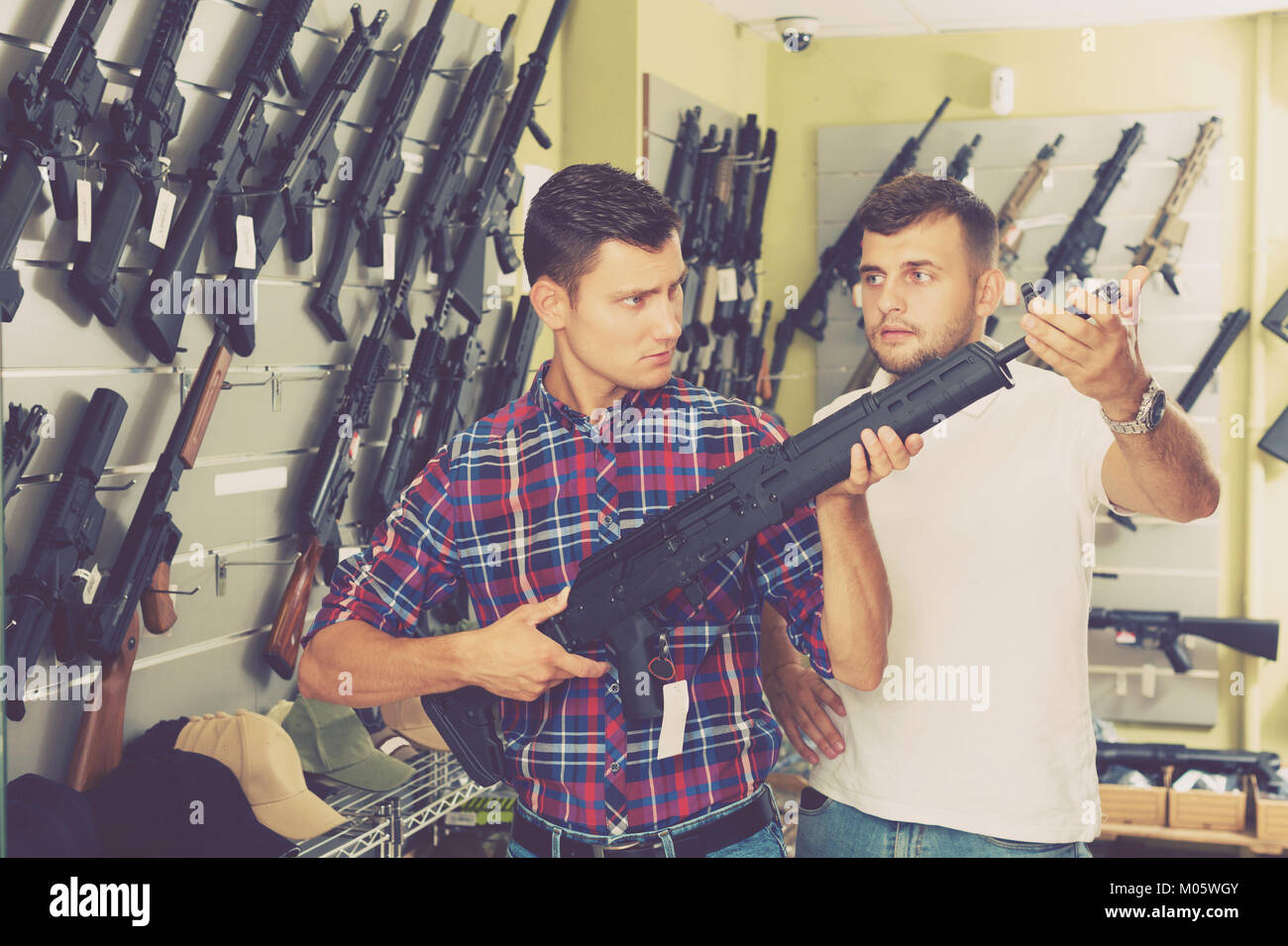 two adult male friends choosing air-powered gun in army market Stock ...