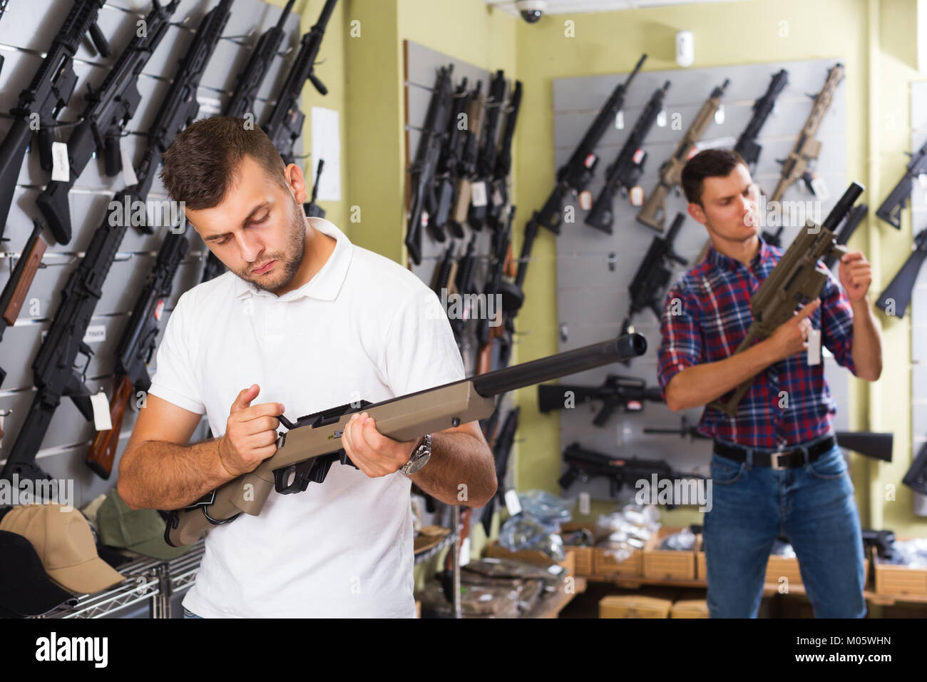 two adult serious friends choosing air-powered gun in army market Stock ...