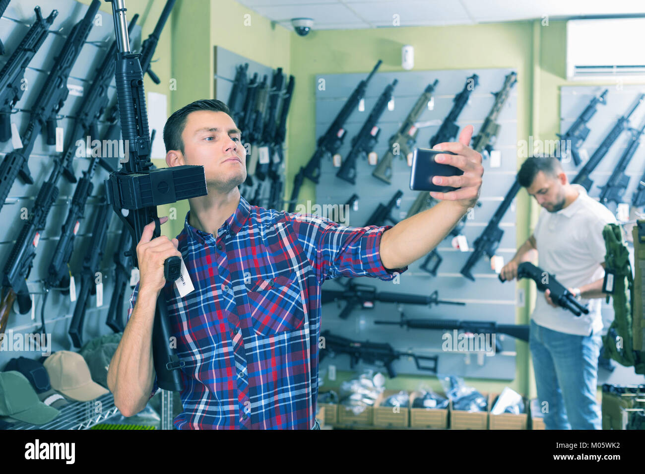 Serious guy taking selfie with rifle in army store Stock Photo - Alamy