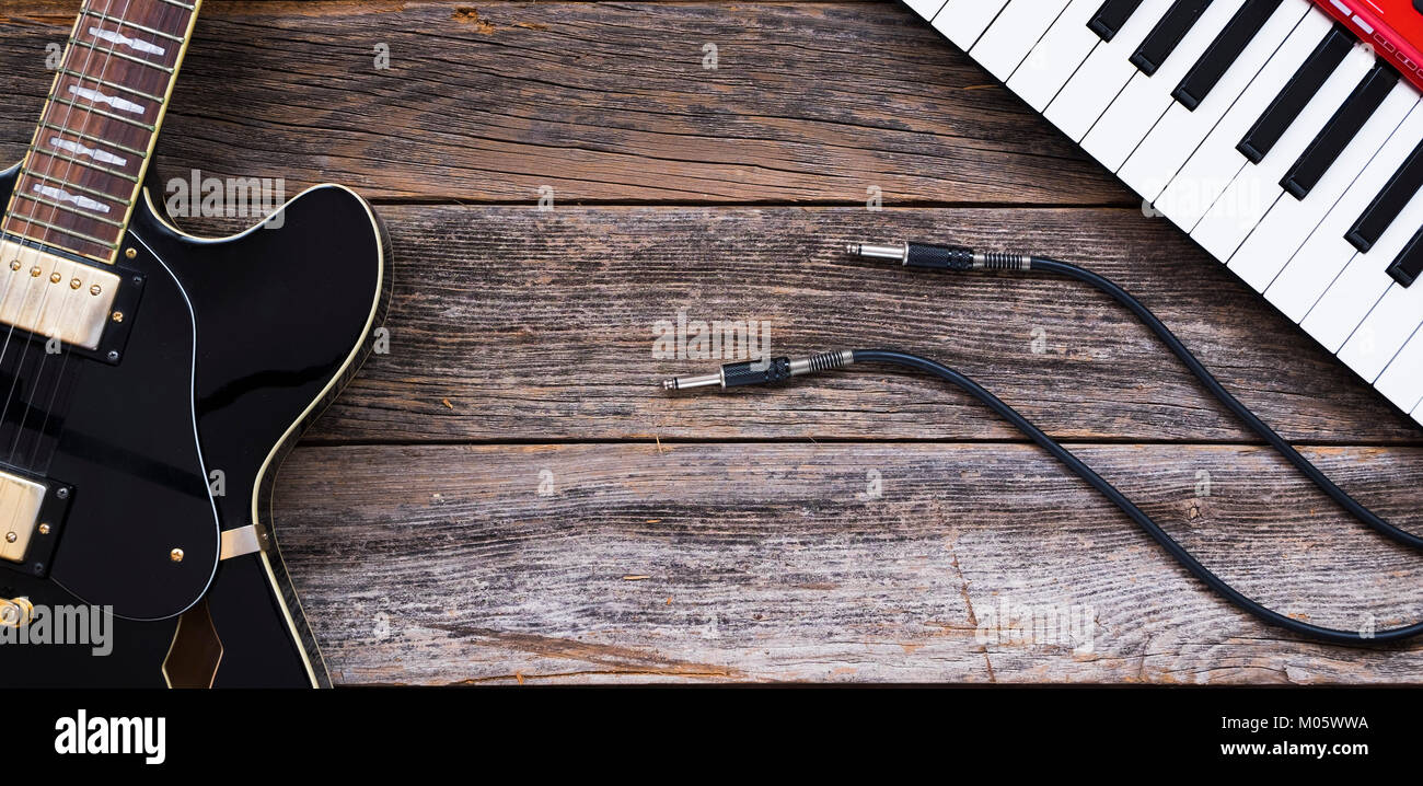 Electric guitar, keyboards and guitar cables on a wooden base Stock ...