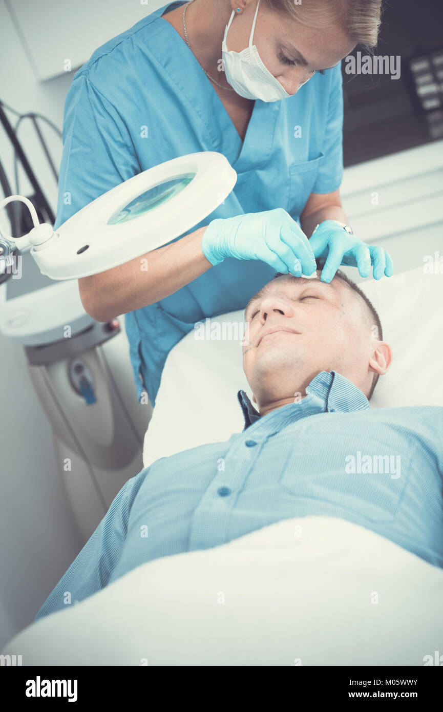 Female doctor is doing cleaning skin procedure to client in cabinet ...