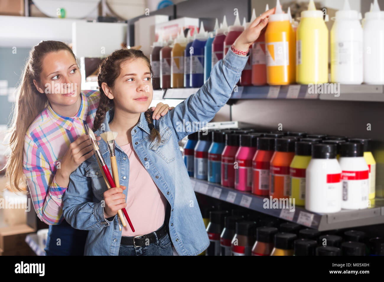 Positive woman and girl shopping acrylic color paints in art store ...