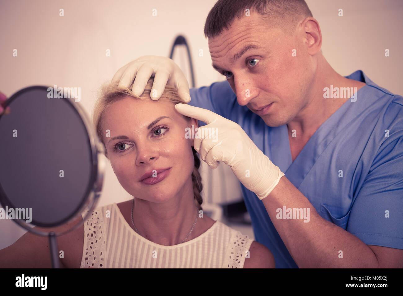 Doctor is examining woman patient behind mirror before the procedure in ...