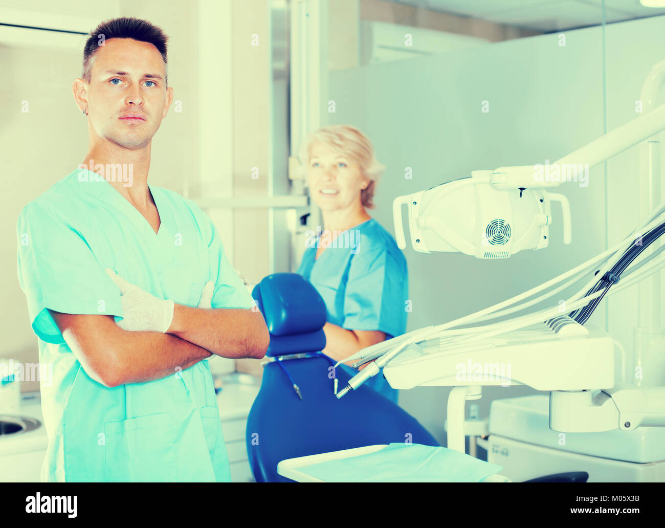 Portrait of professional male dentist with arms crossed with dental ...