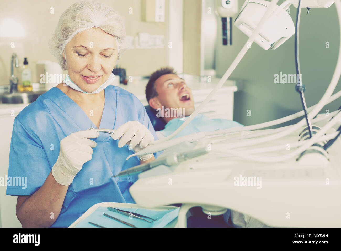 Portrait of professional dentist in dental clinic with patient behind ...