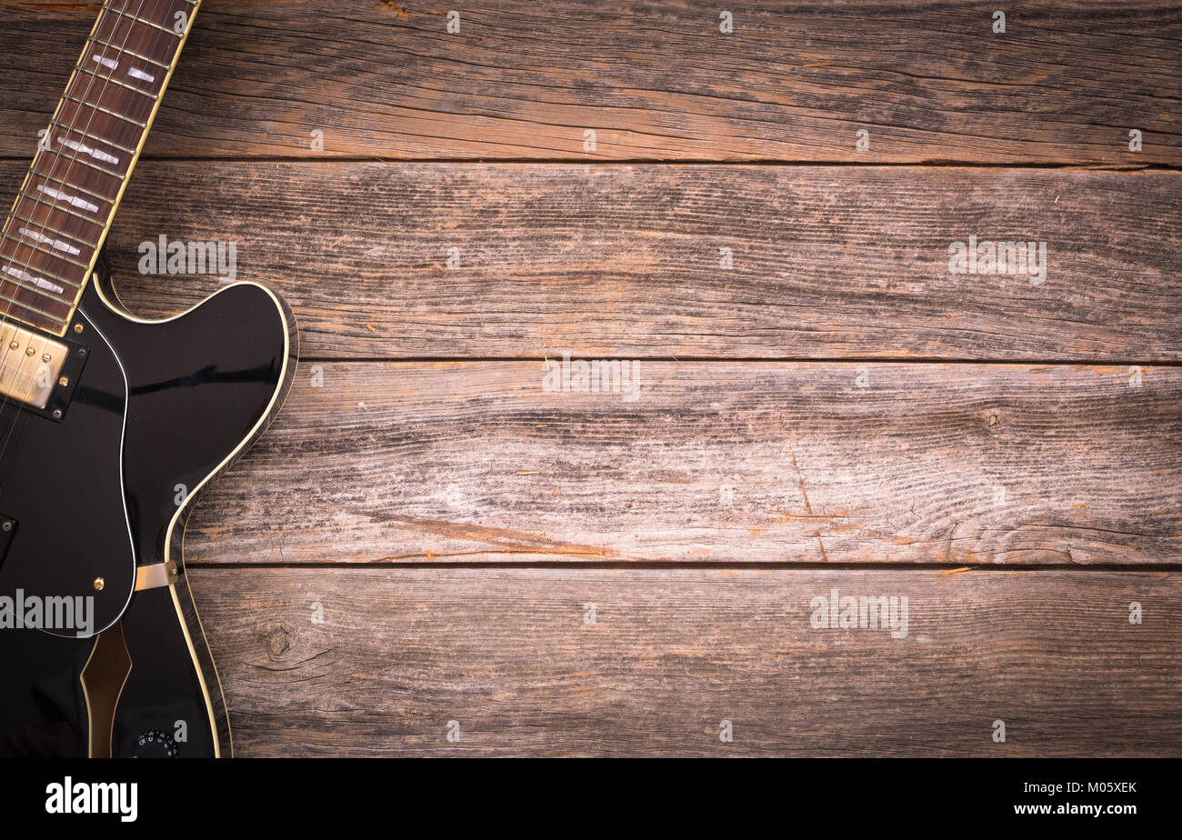 Black electric guitar on a rustic wooden background Stock Photo - Alamy