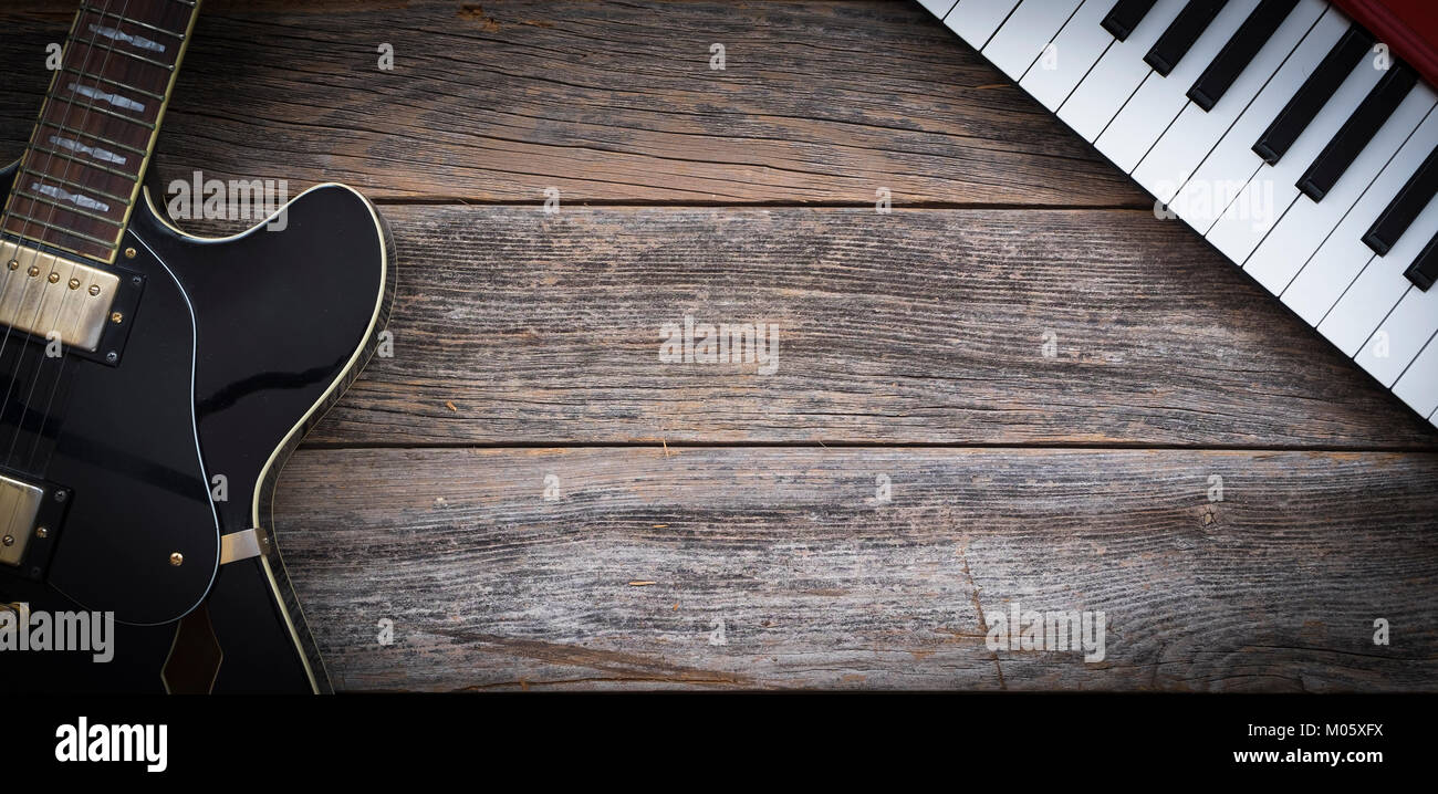 Black electric guitar and keyboard on a rustic wooden background Stock ...