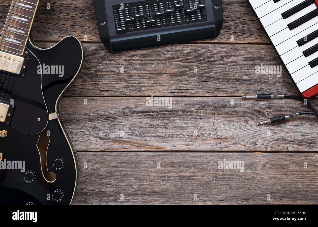Electric guitars, keyboards, mixing board and cables on a wooden ...