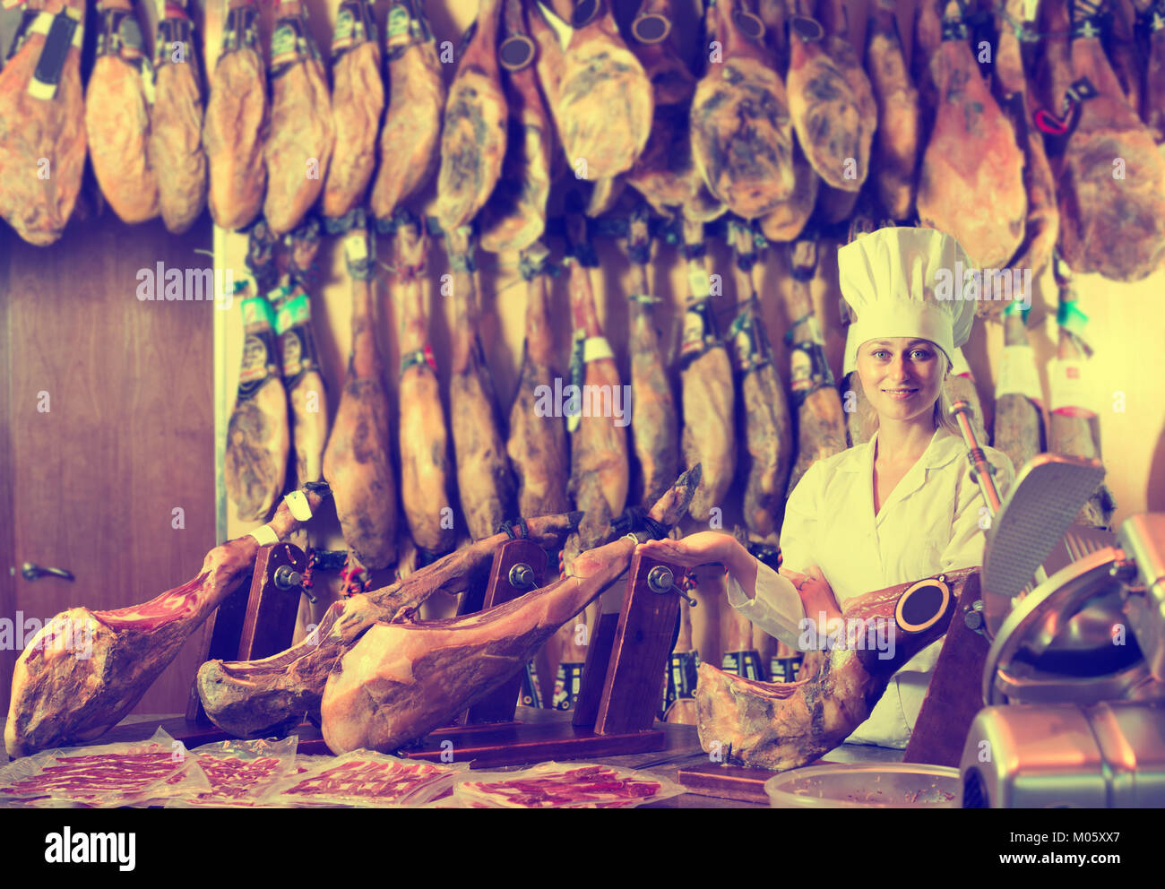 glad young woman in uniform working with fresh meat in counter on ...