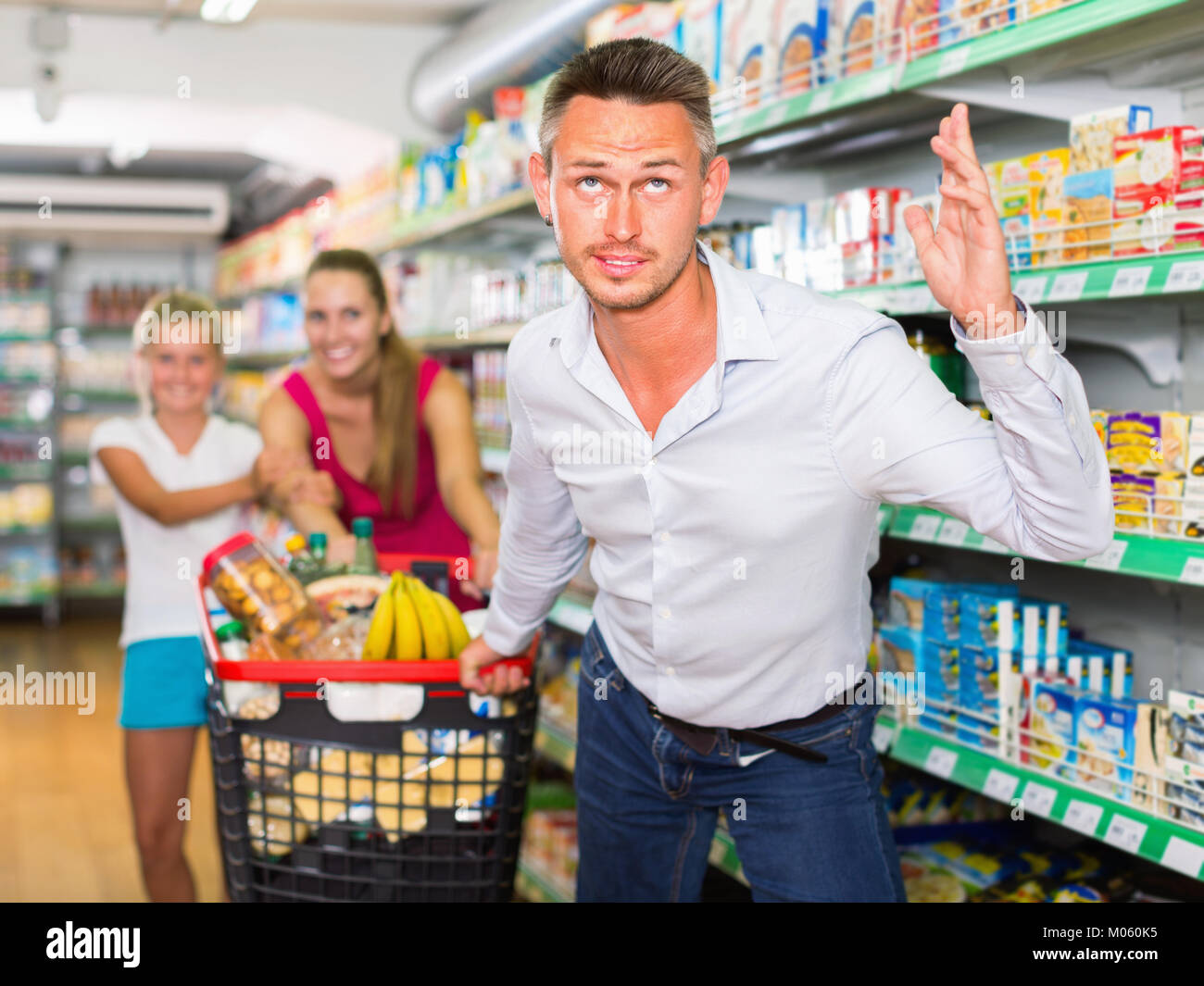 Unhappy male customer with family and purchases in shopping cart Stock ...