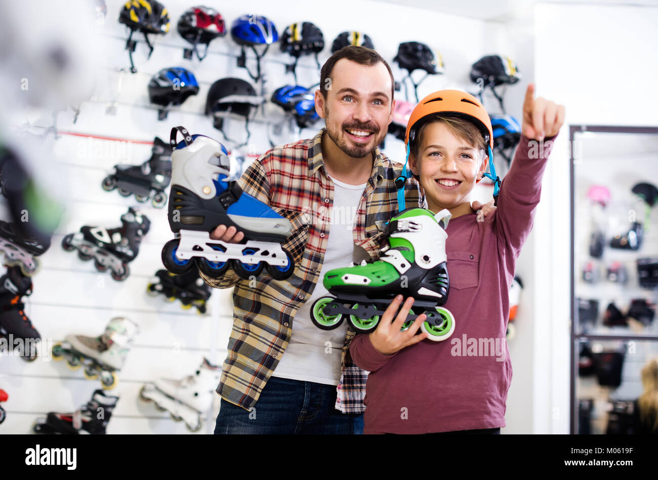 positive american male shop assistant helping boy to choose roller ...