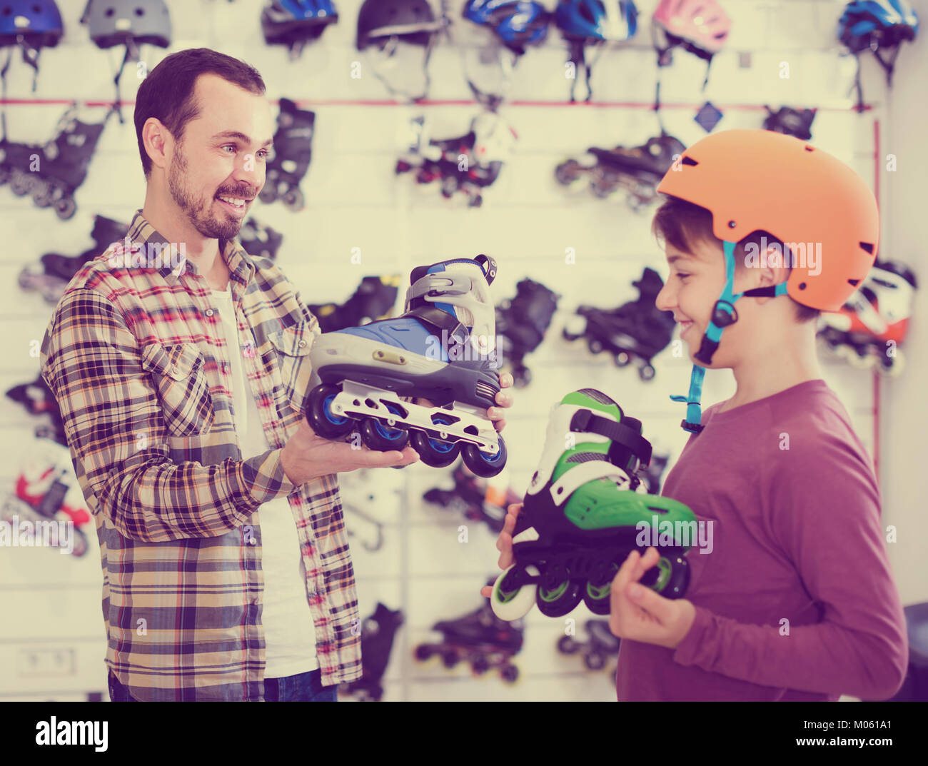 happy germany male shop assistant helping boy to choose roller-skates ...