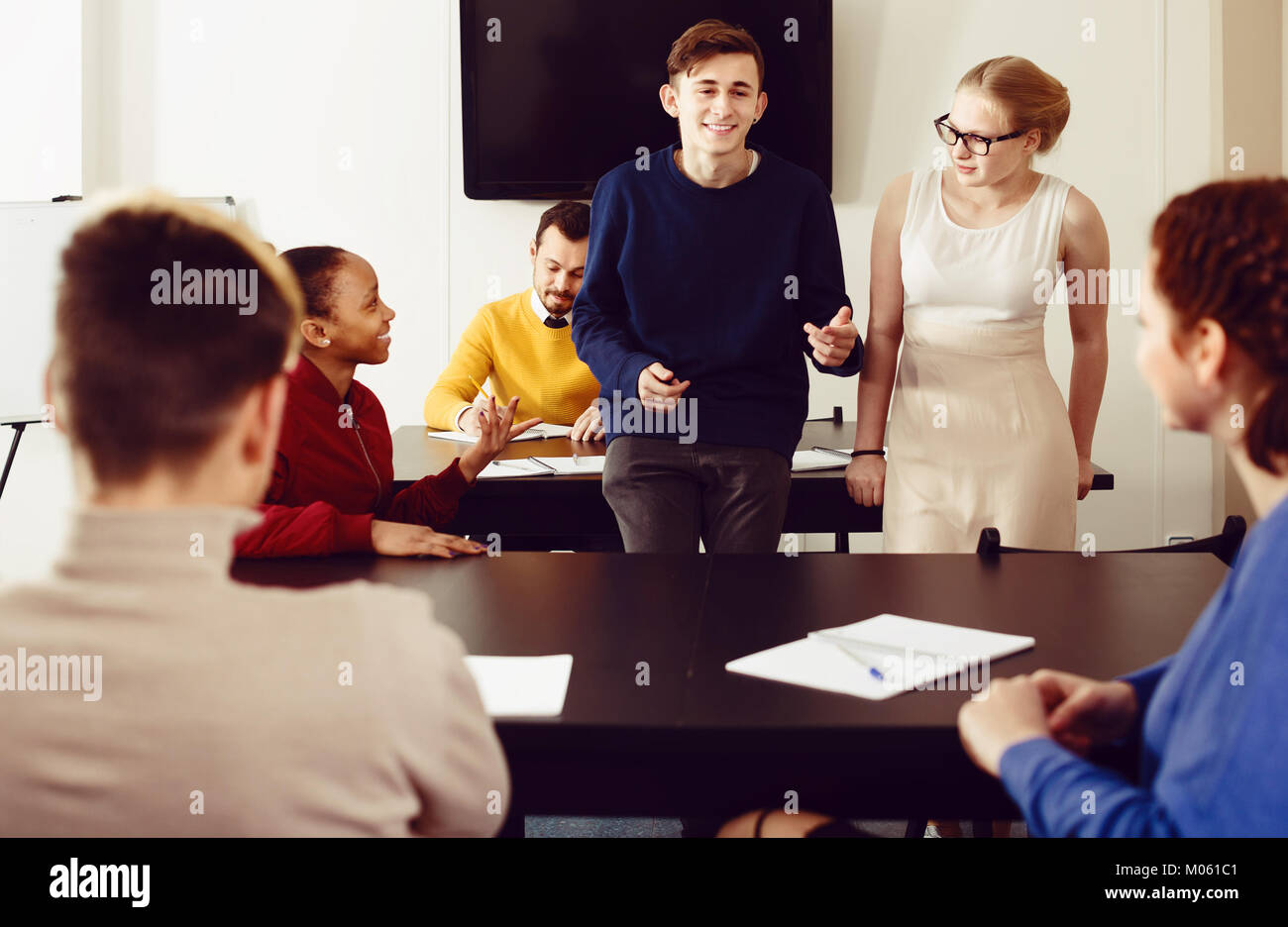 smiling classmates having animated talks at break between classes sits ...