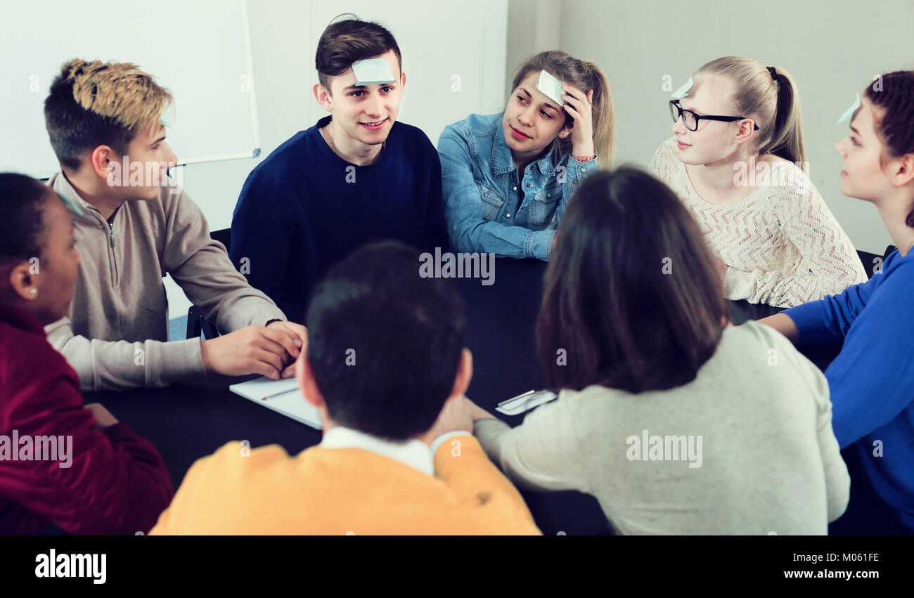 happy american classmates having round of guess-who game during class ...