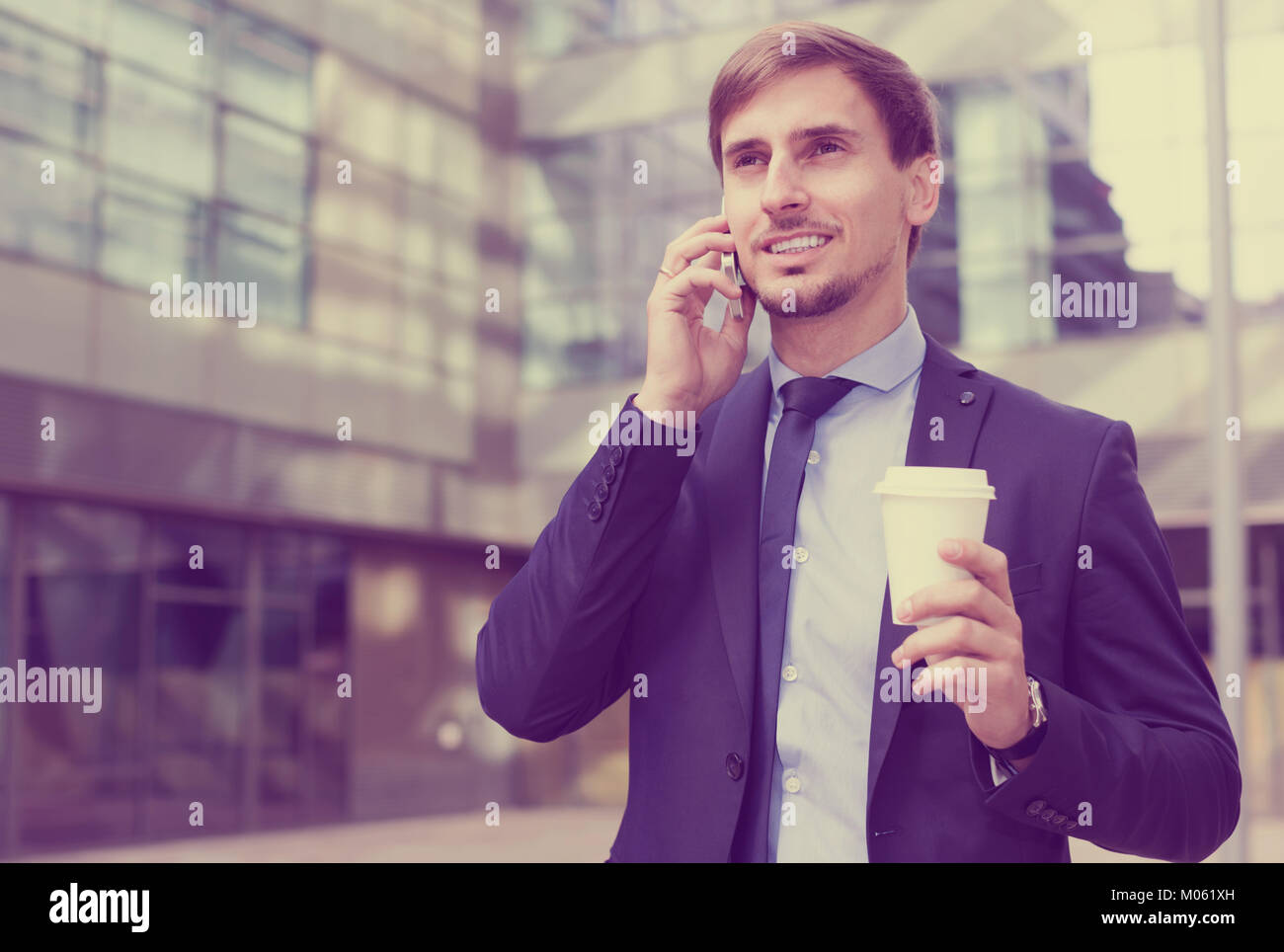 Portrait of male worker talking on the phone with coffee on the hand ...