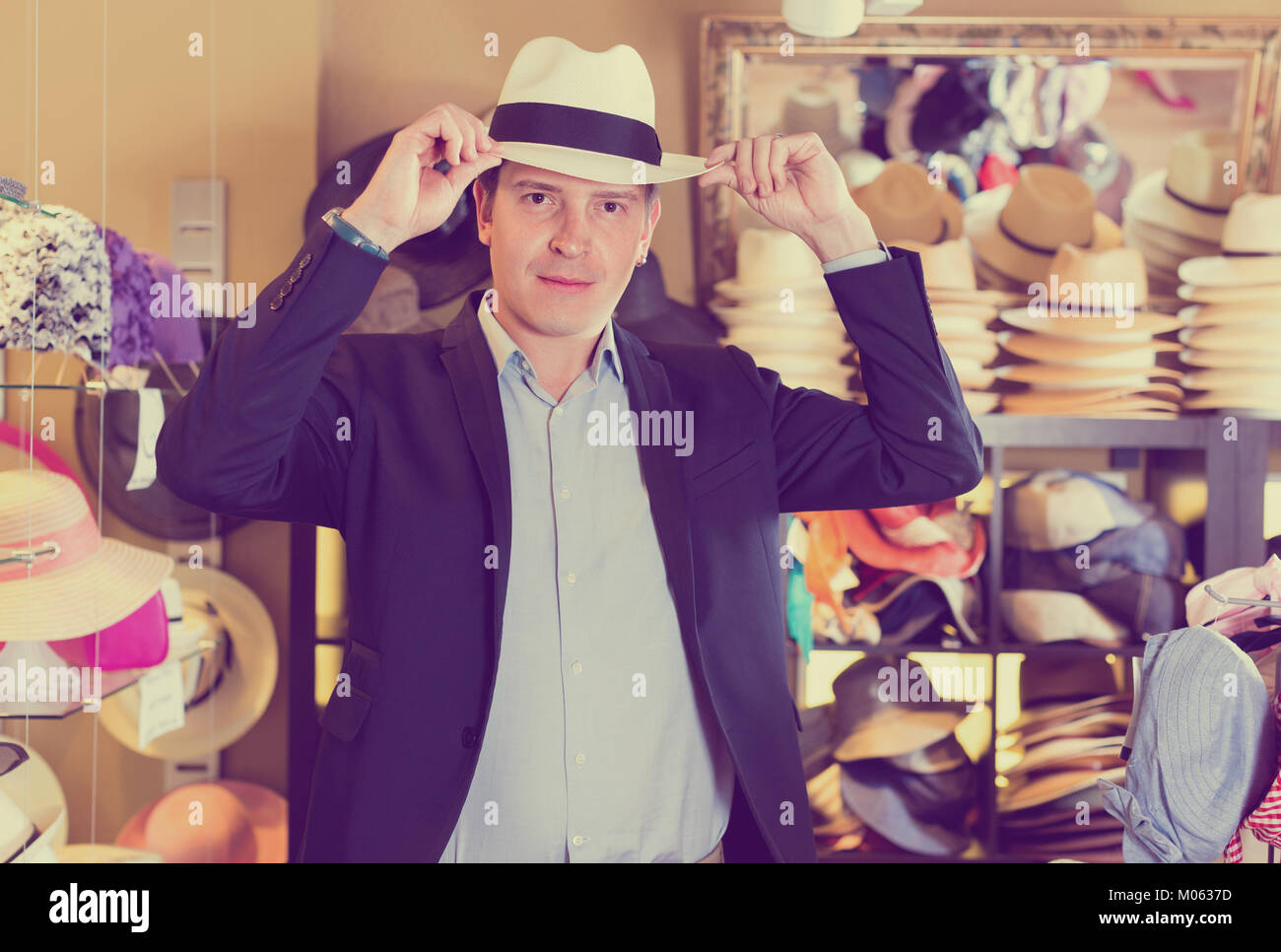 Portrait of cheerful positive smiling young guy try on sun hat at ...
