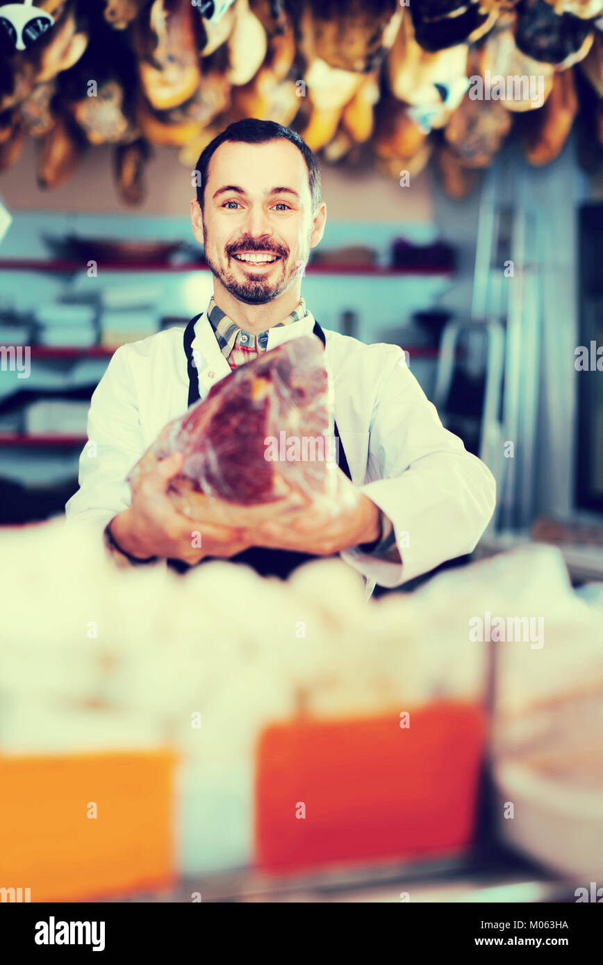 happy european male shop assistant demonstrating piece of meat in ...