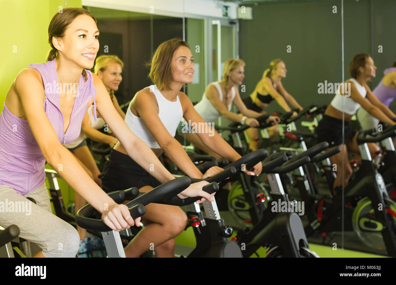 Sporty positive women on cardio training on exercycles in health club ...