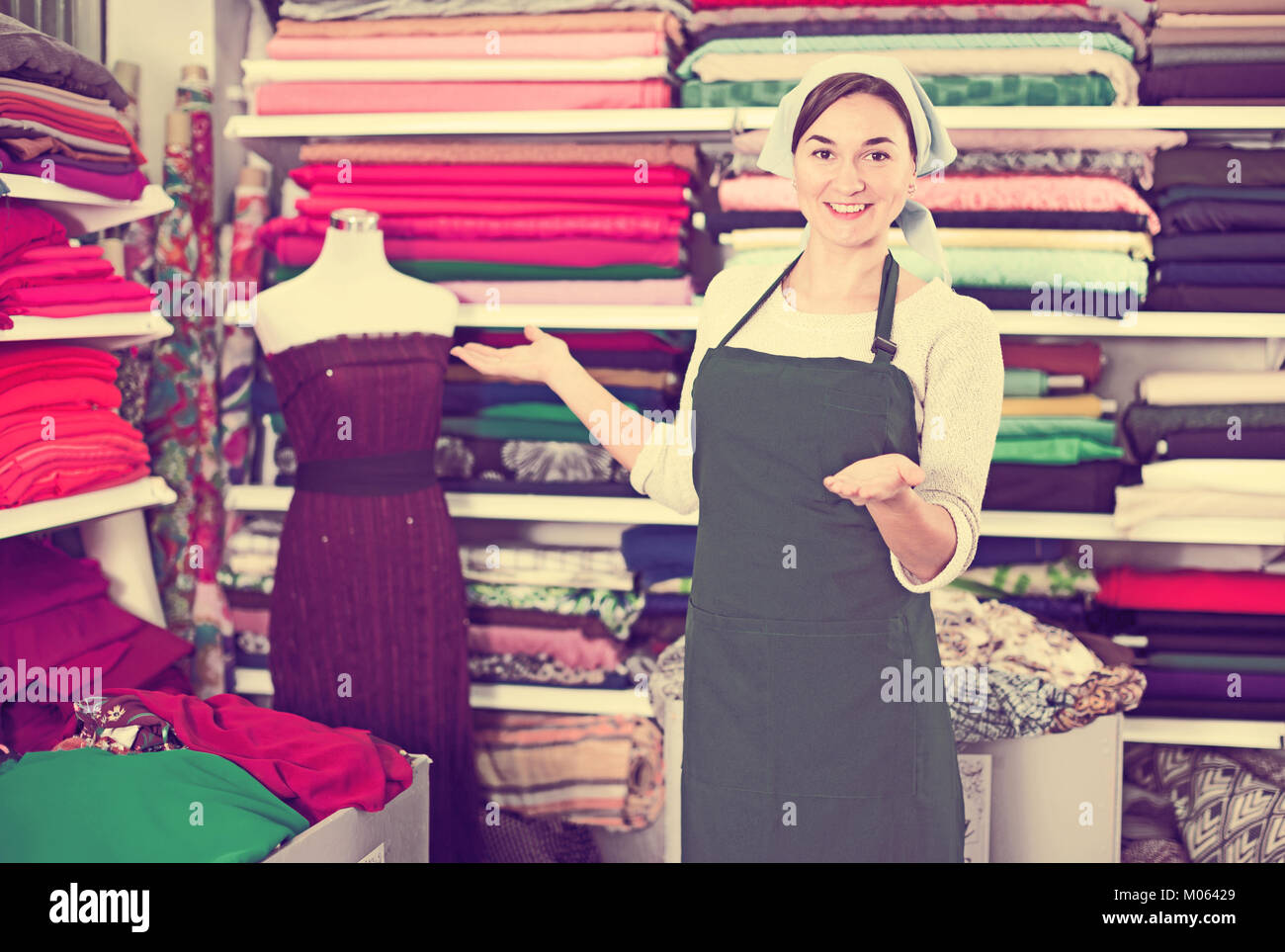 Young woman seller displaying various fabrics at drapery shop Stock ...