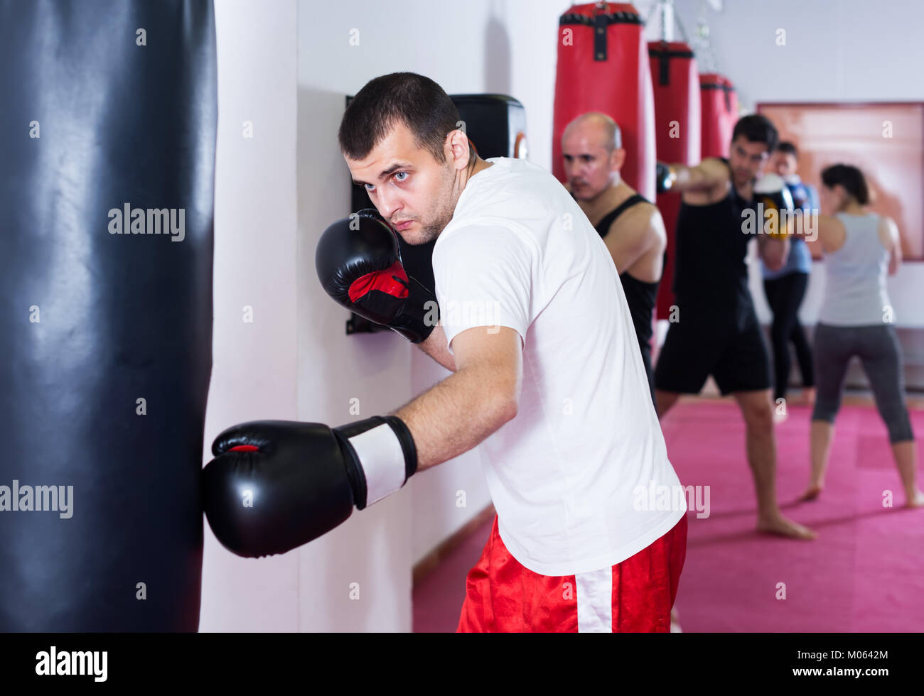 converging sportsman in the boxing hall practicing boxing punches with ...