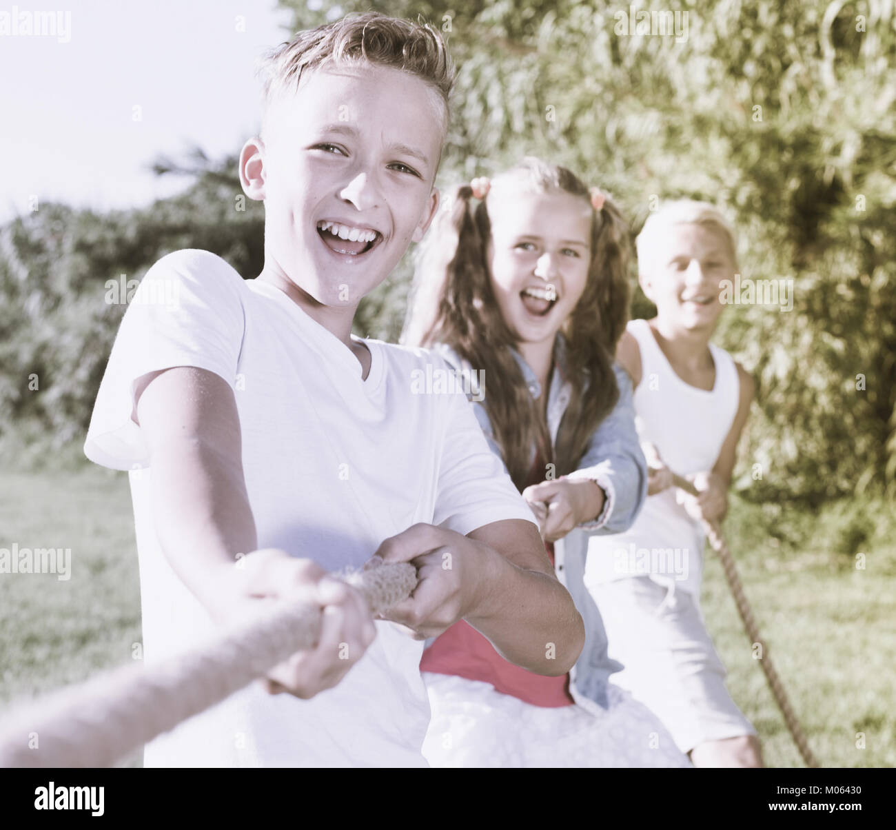 Children playing tug of war during joint games outdoors on sunny day ...