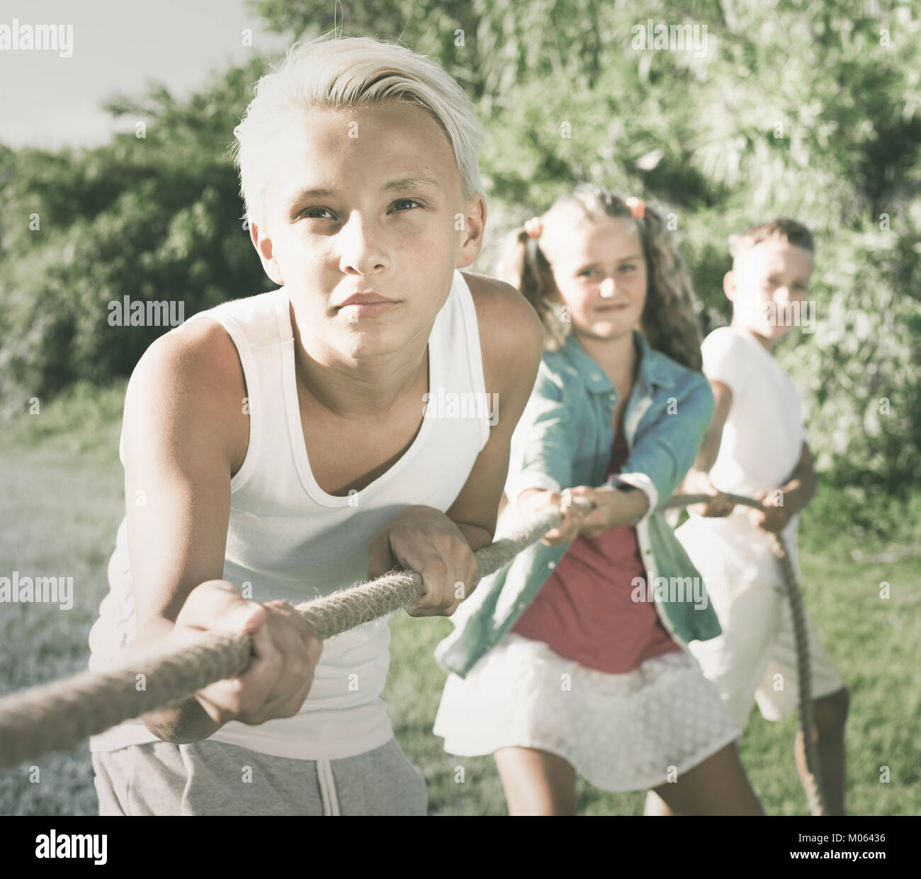 Children playing tug of war during joint games outdoors on sunny day ...