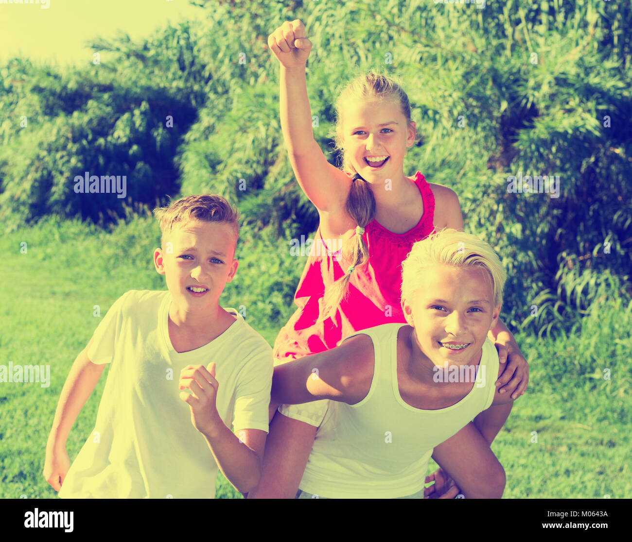 Cheerful girl with two friends having fun together running on summer ...