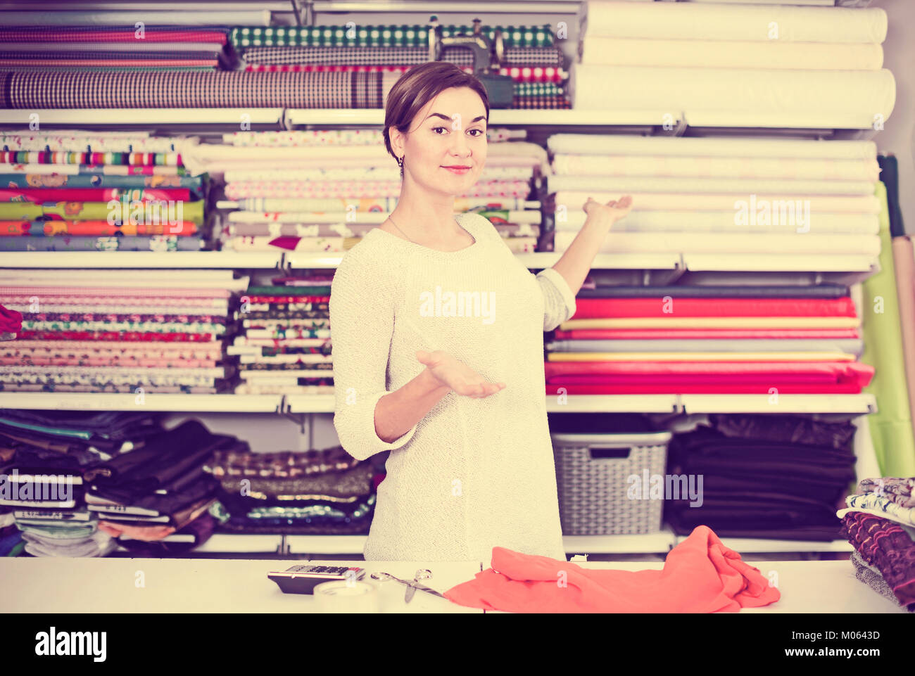 Young woman seller measuring square of cloth at drapery shop Stock ...