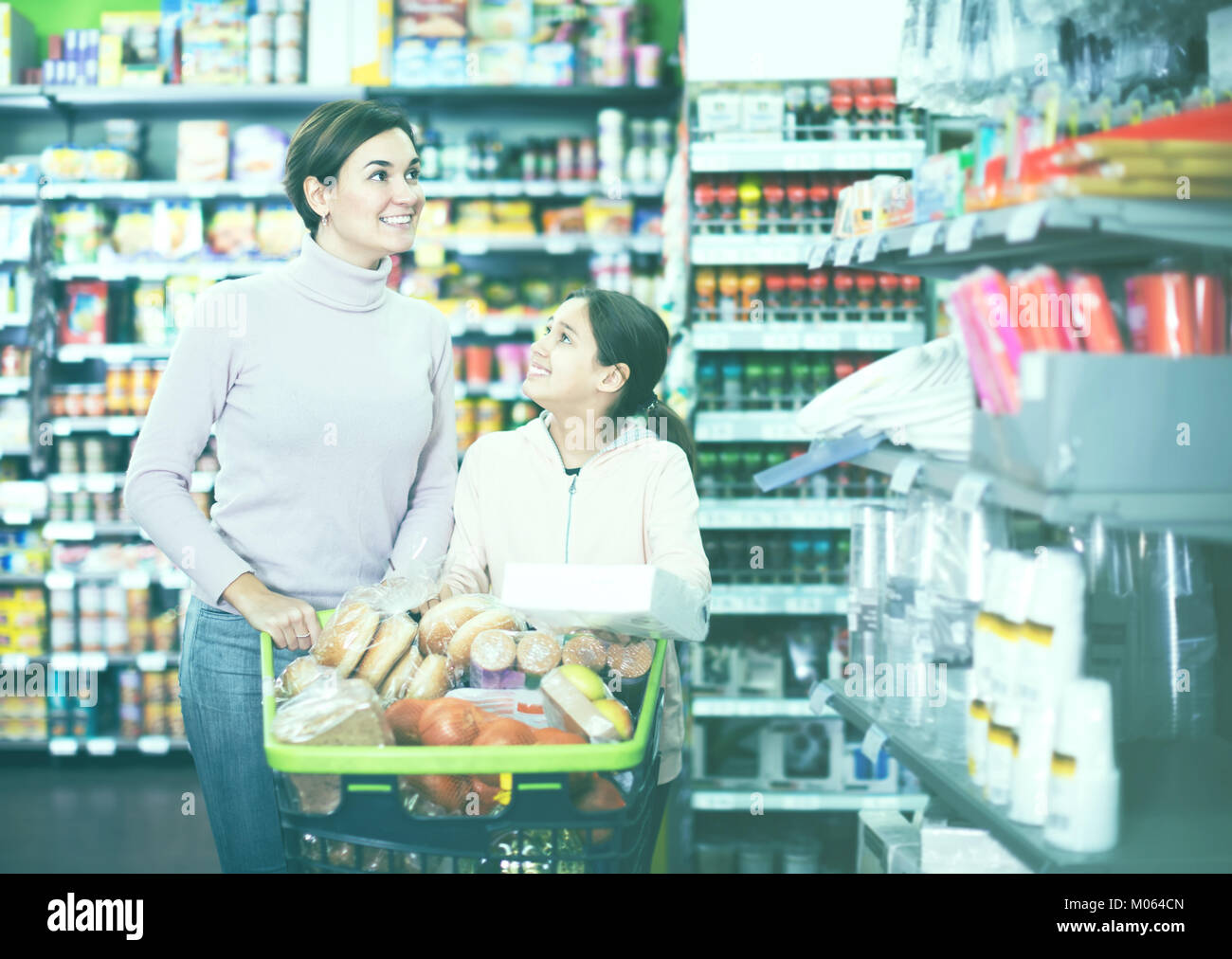 Positive female customer with teenage daughter restocking for family in ...