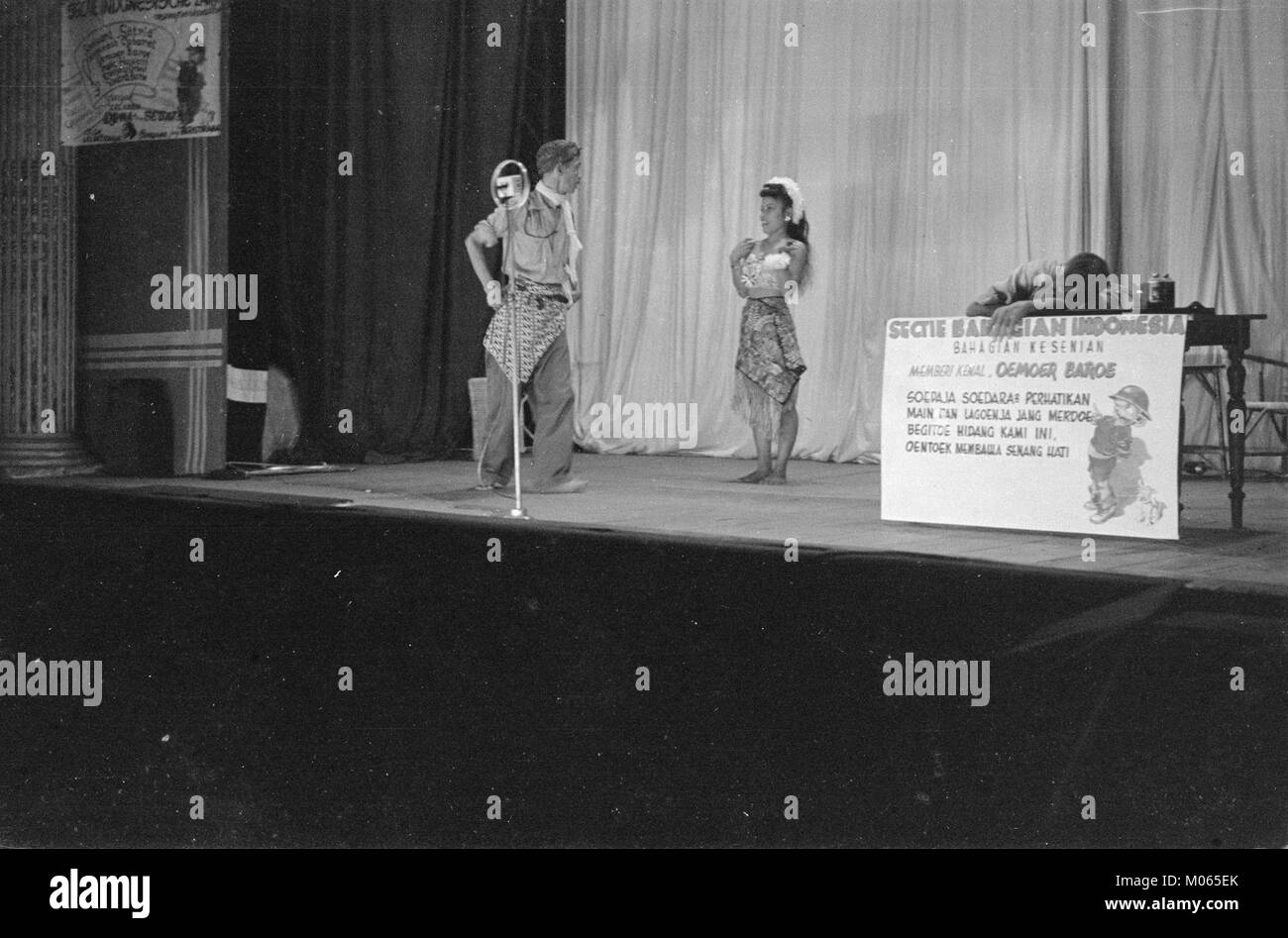 This image depicts a cabaret performance, with a man sitting hunched ...